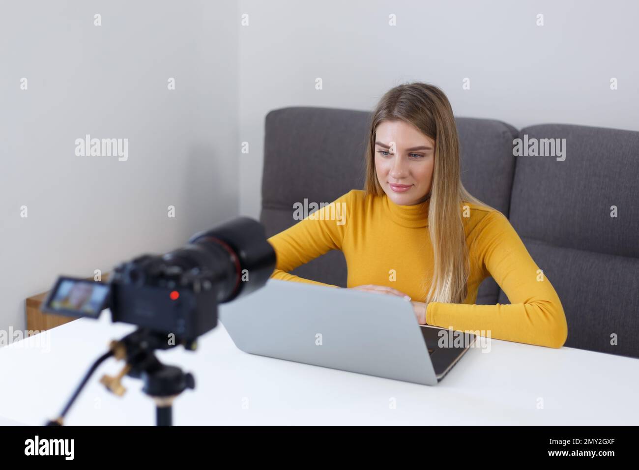 Beautiful young adult woman filming video blog content at home ...