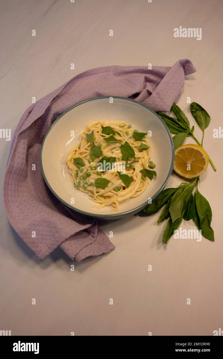 Creamy pasta dish with basil dressing. On white marble background with ...