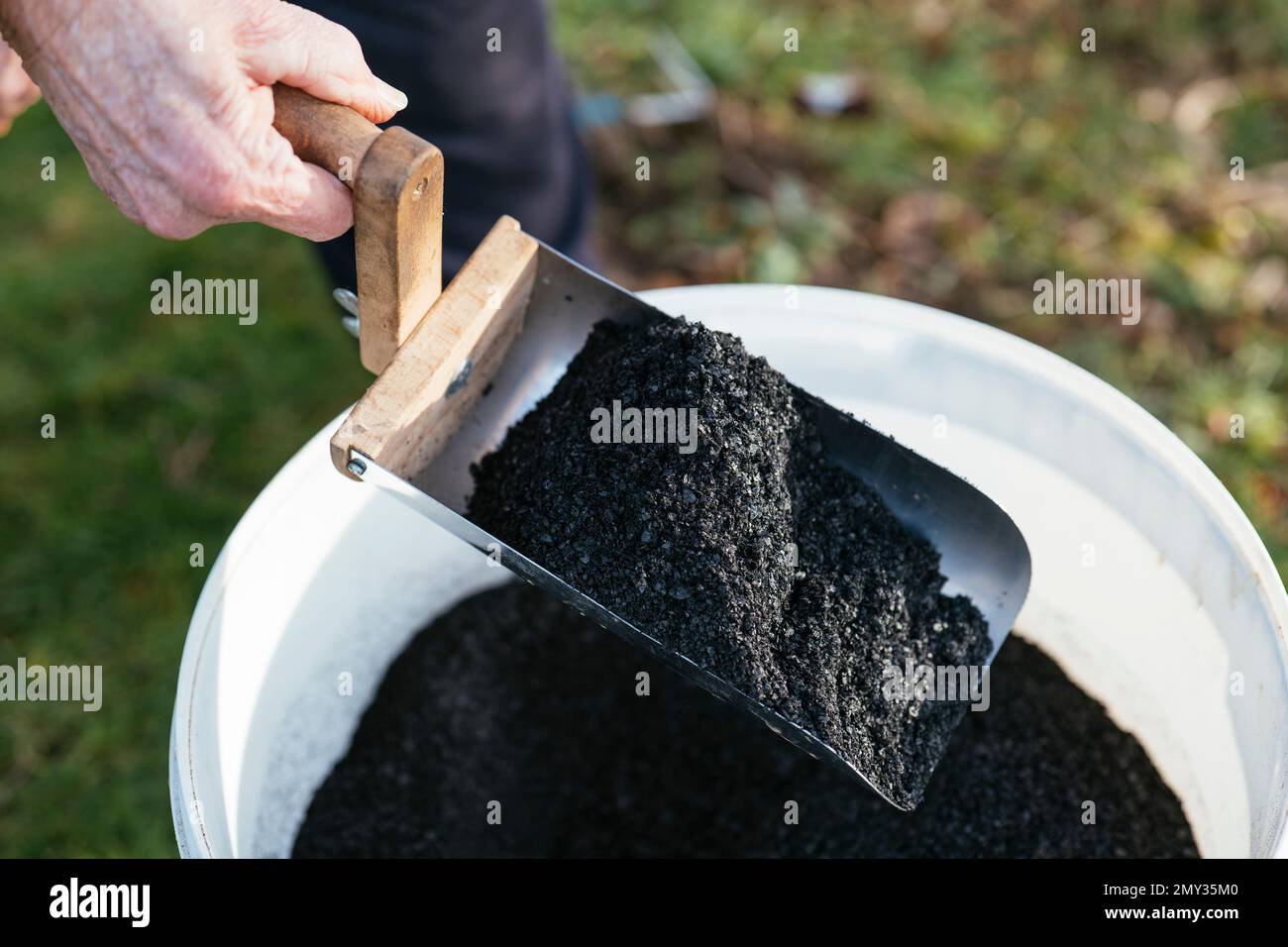 Gardener with a scoop of biochar pellet made from herbs using pyrolysis ...