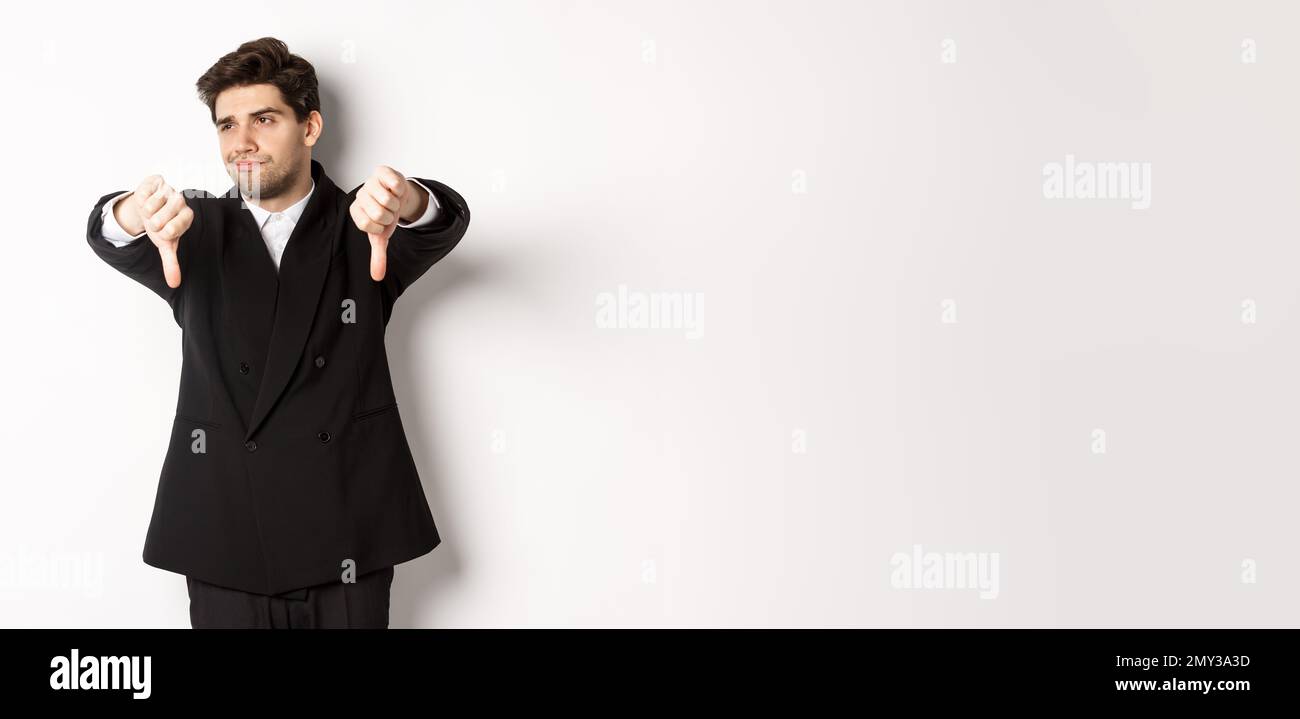 Skeptical and displeased man in black suit, looking away reluctant ...