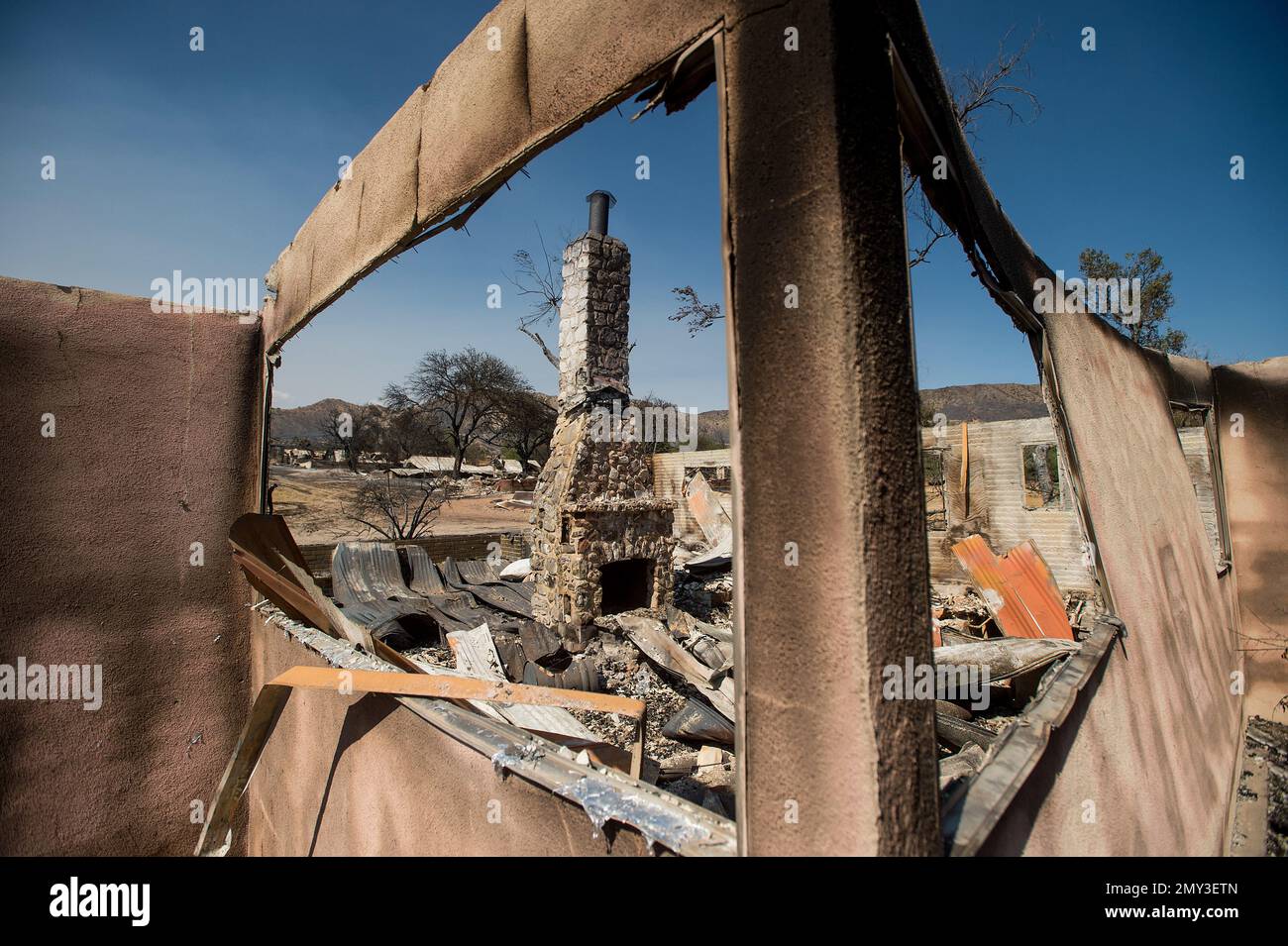 A chimney stands amid rubble at a house scorched by a wildfire in ...