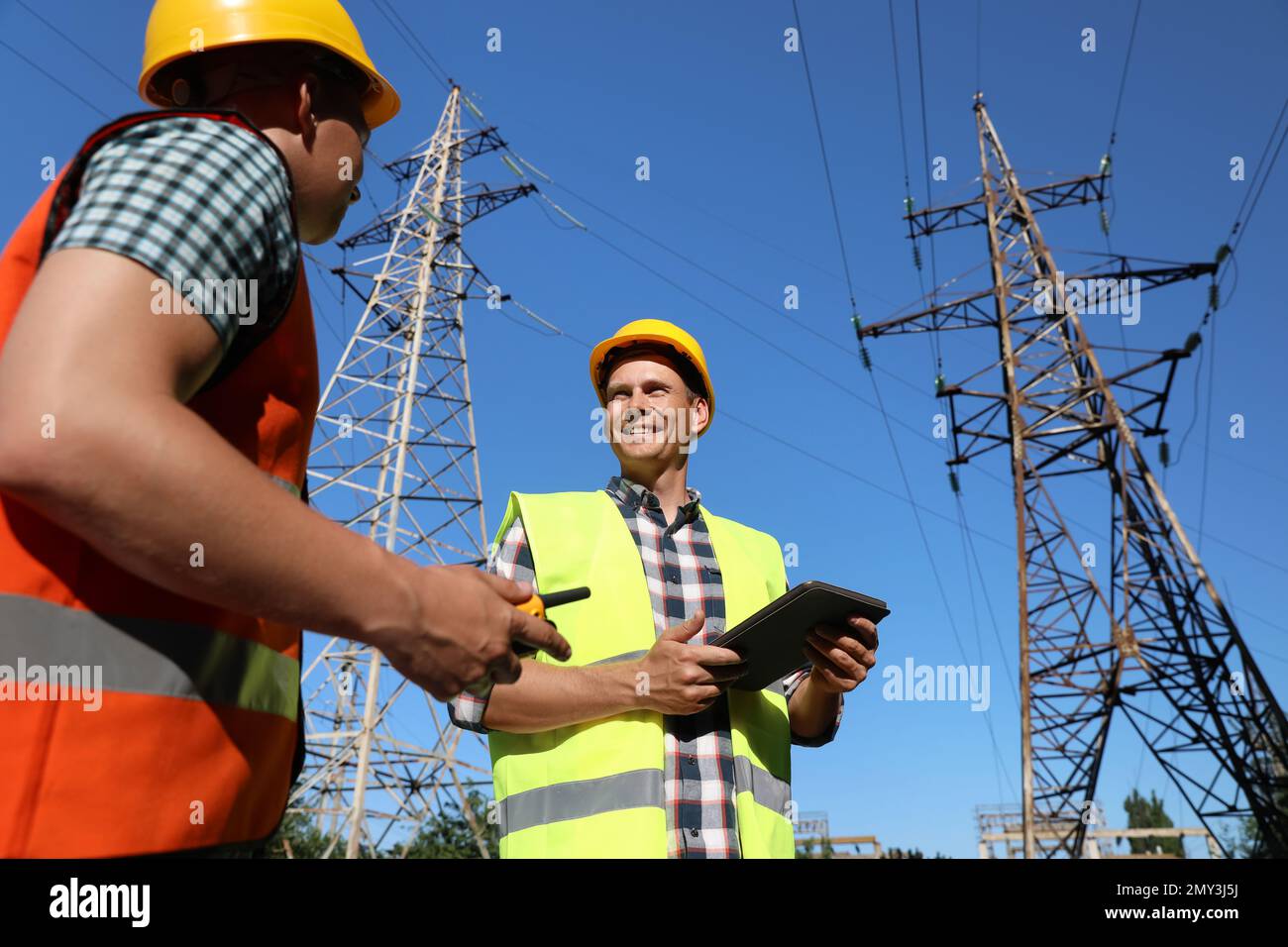 Professional electricians in uniforms near high voltage towers Stock ...