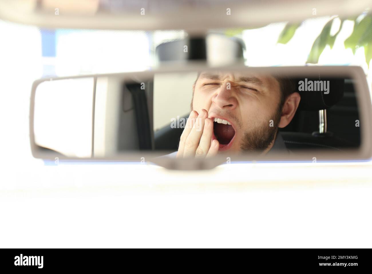 Tired man yawning while driving, reflection in rearview mirror Stock ...