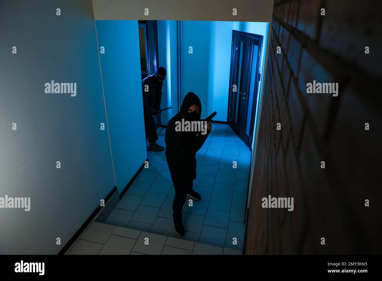 Dangerous criminals in masks with weapon in hallway Stock Photo - Alamy