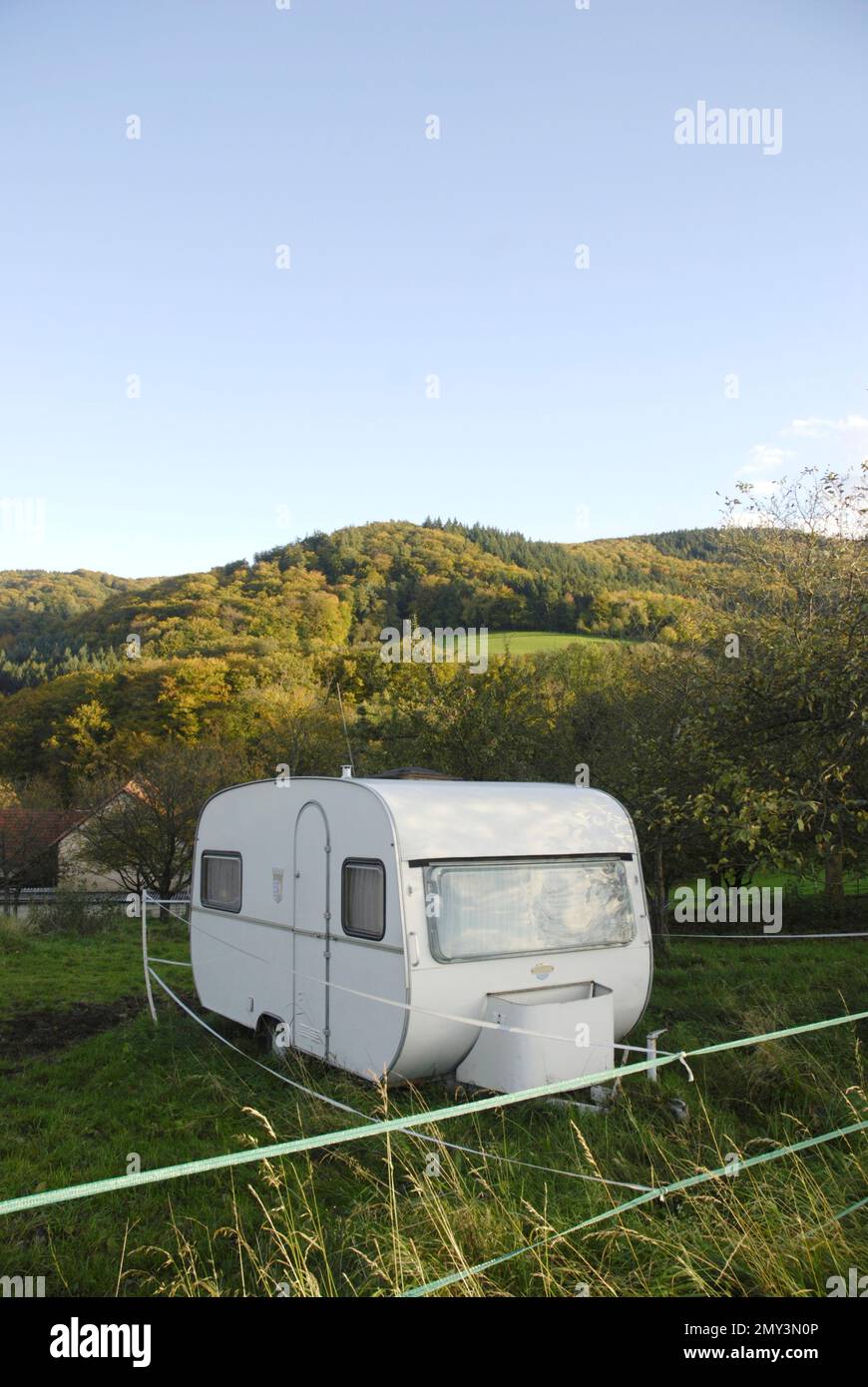 Parked caravan on a fenced plot in front of a hilly landscape Stock ...