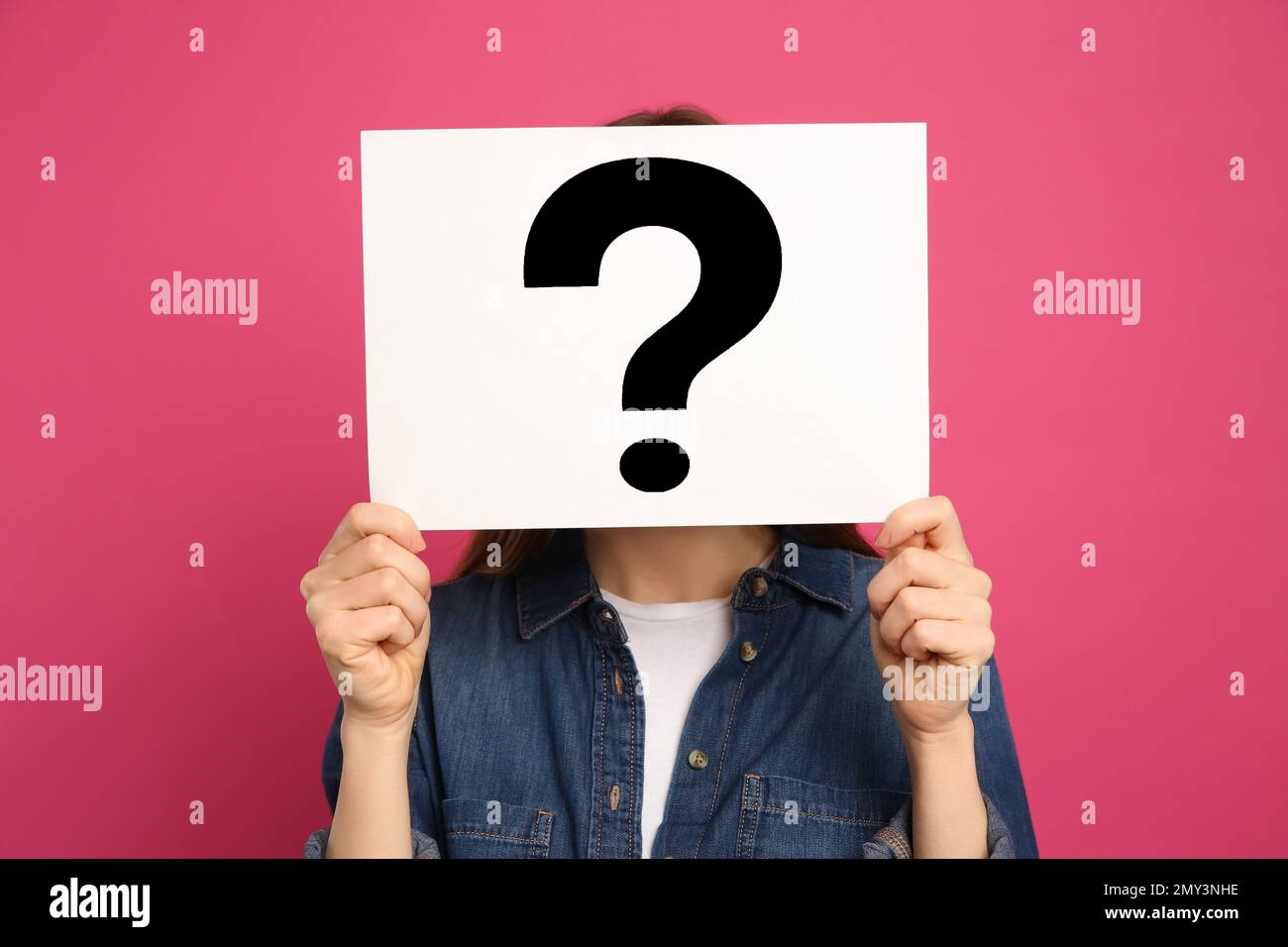 Woman holding question mark sign on pink background Stock Photo - Alamy