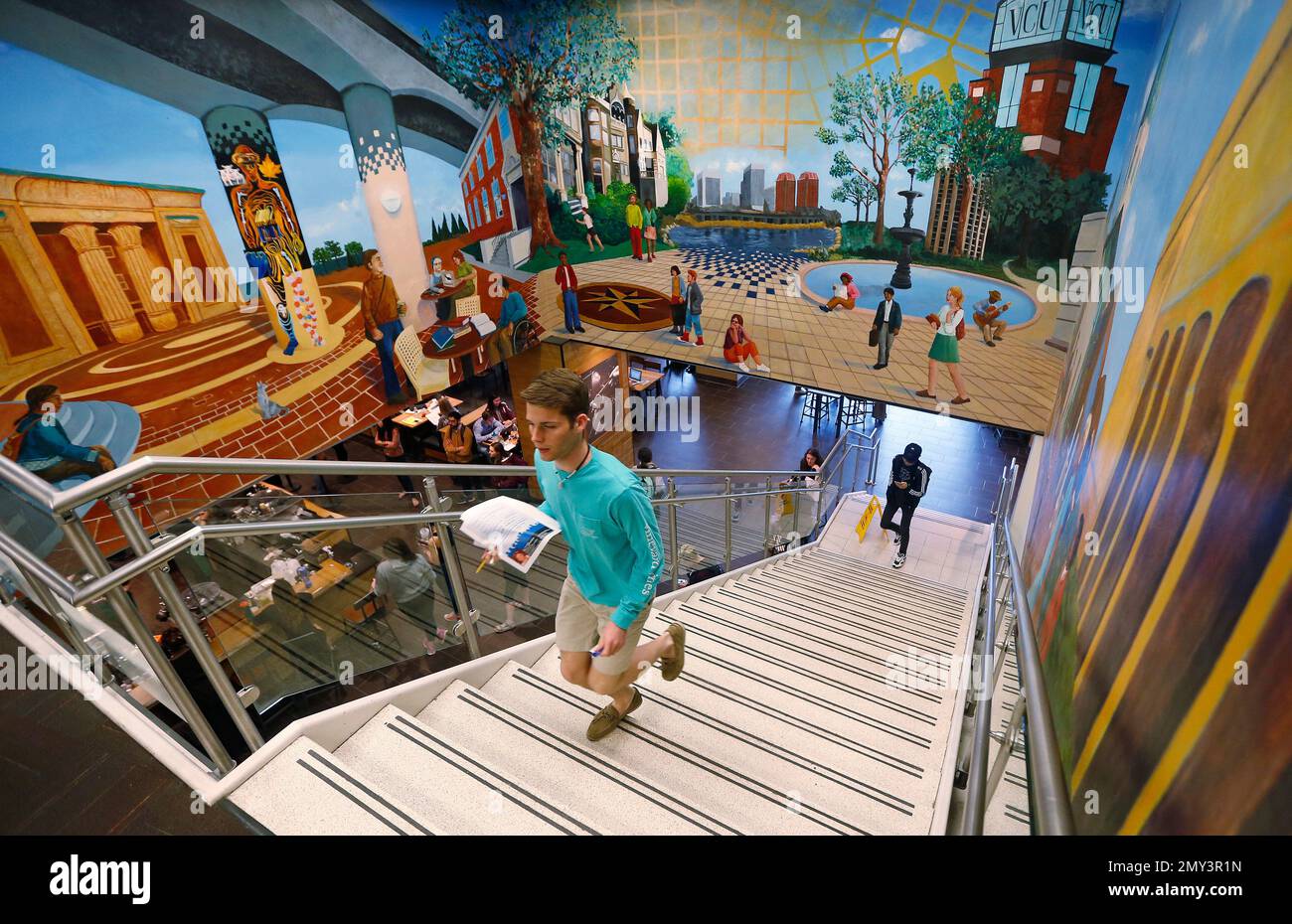 A student walks up stairs surrounded by colorful murals at the ...