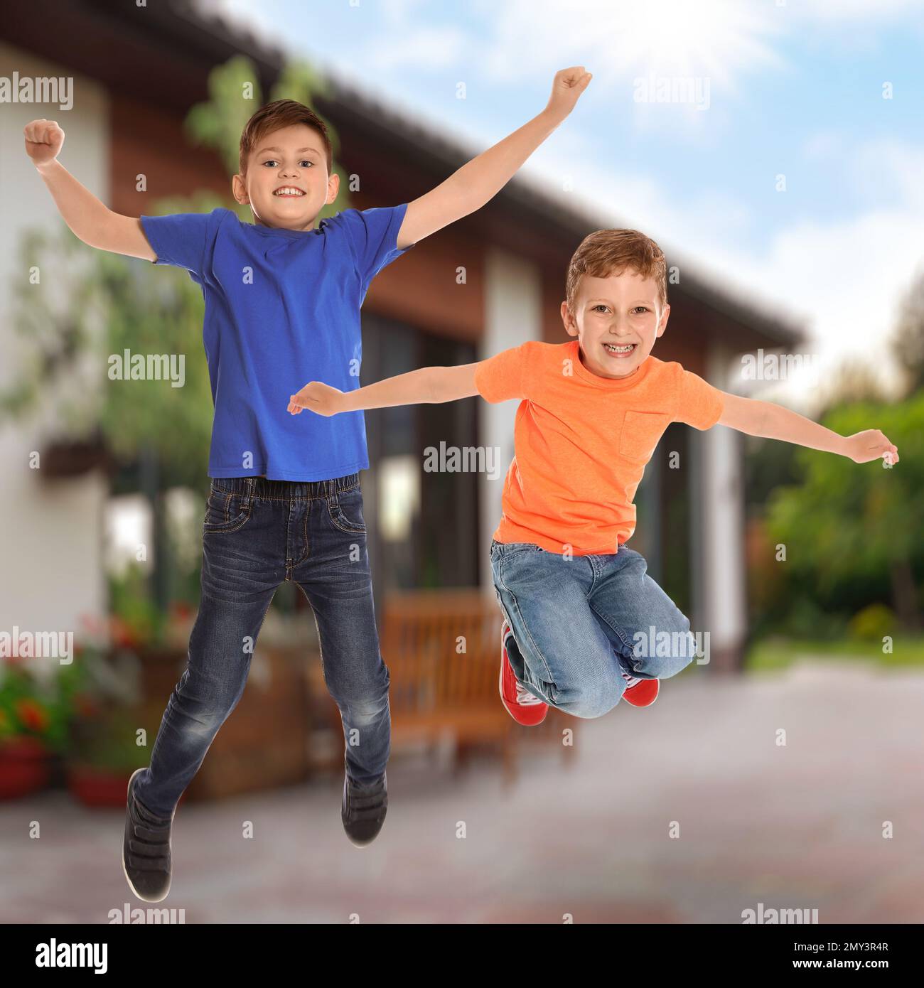 Happy boys jumping near house. School holidays Stock Photo - Alamy
