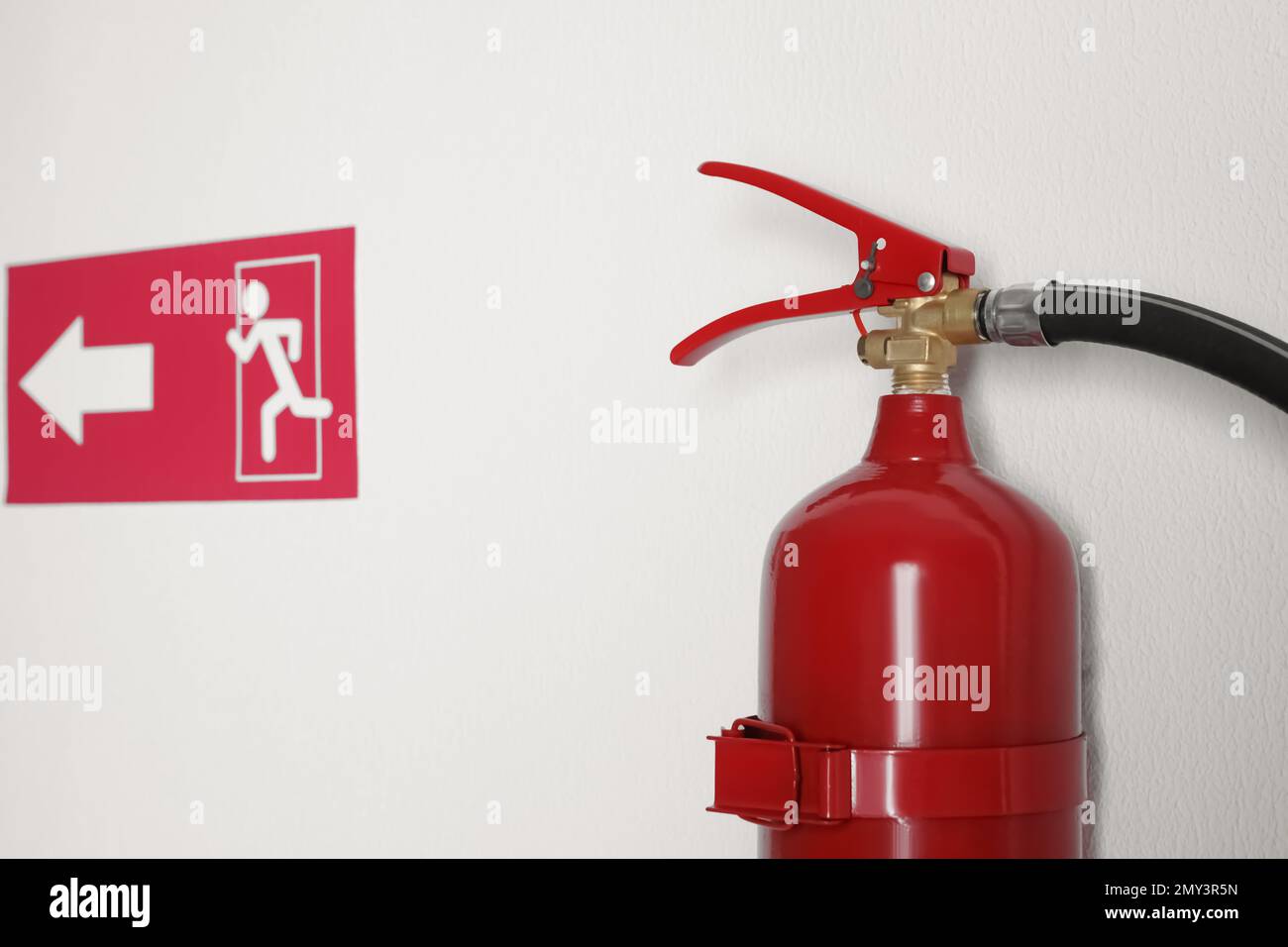Fire extinguisher and emergency exit sign on white wall, closeup Stock ...