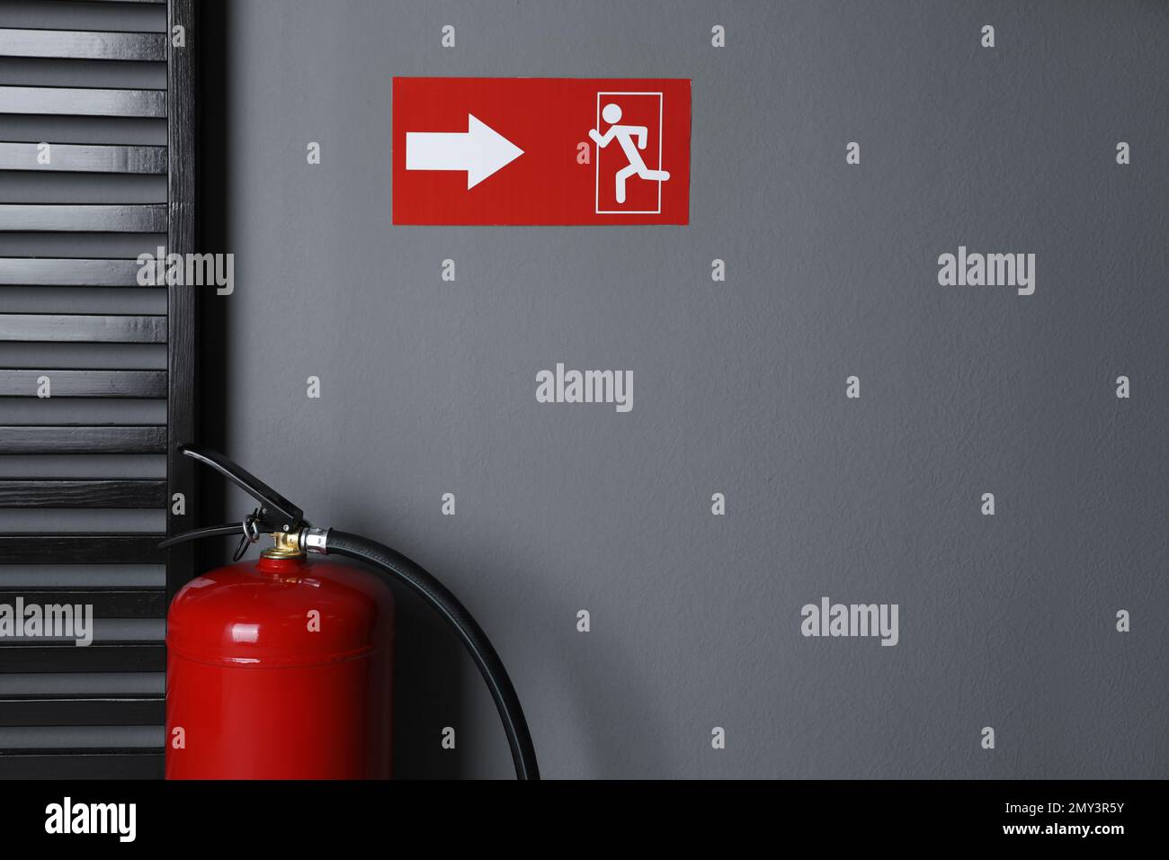 Fire extinguisher and emergency exit sign indoors. Space for text Stock ...