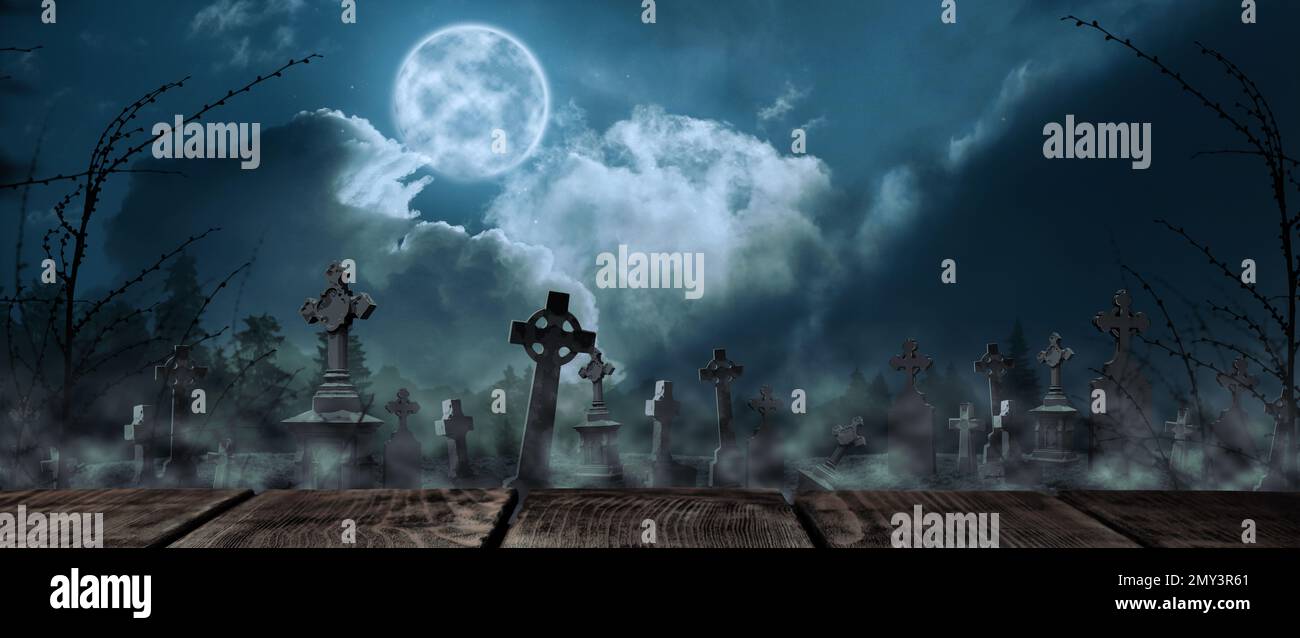 Wooden surface and misty graveyard with old creepy headstones under ...