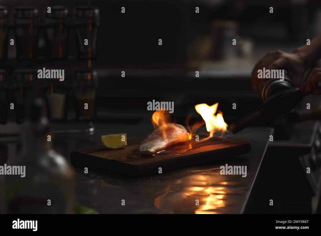 Female chef cooking chicken fillet with manual gas burner in restaurant ...