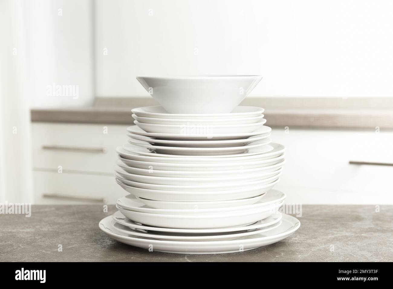 Stack of clean plates on marble table in kitchen Stock Photo - Alamy