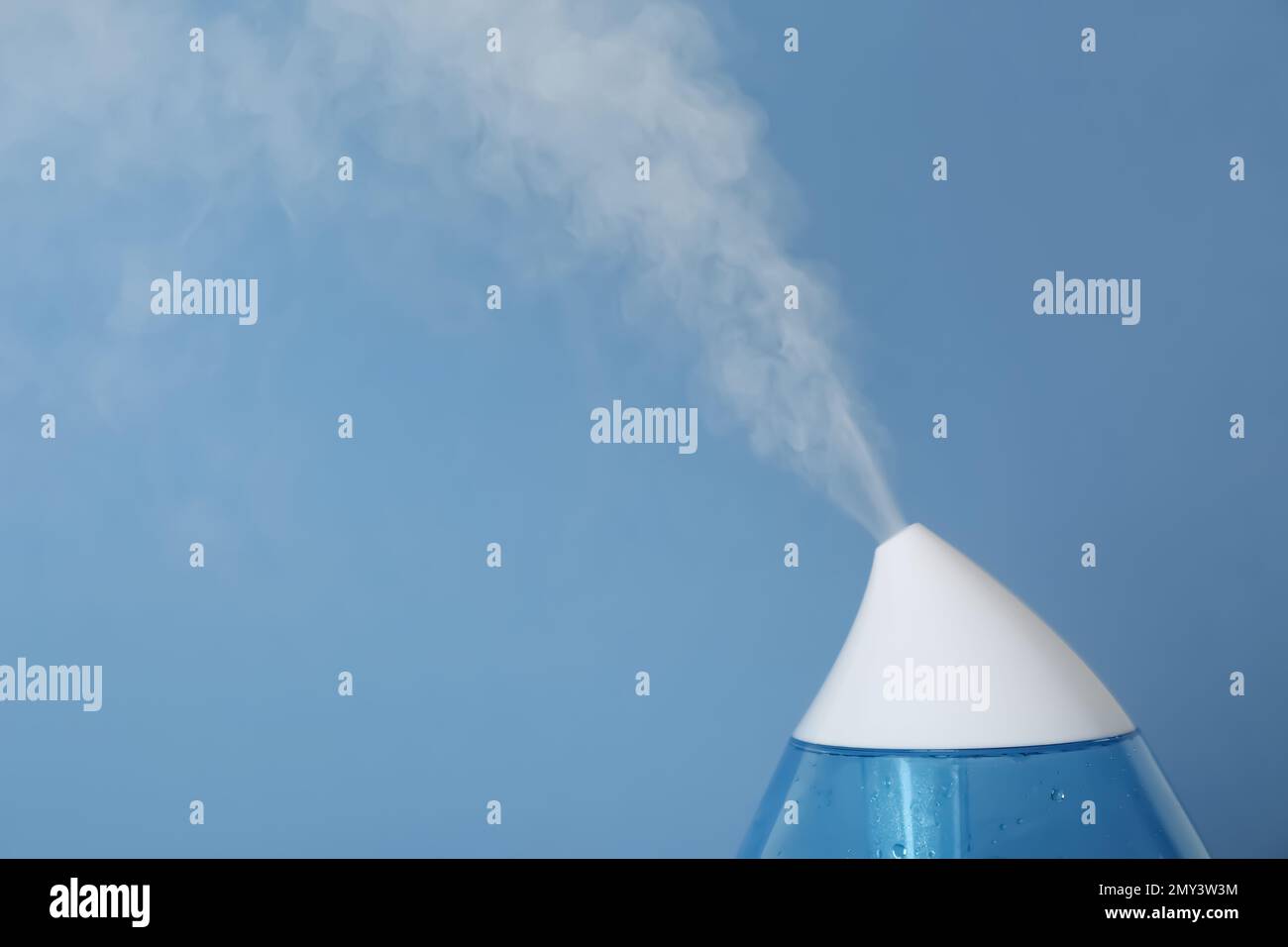 Modern air humidifier on light blue background, closeup. Space for text ...