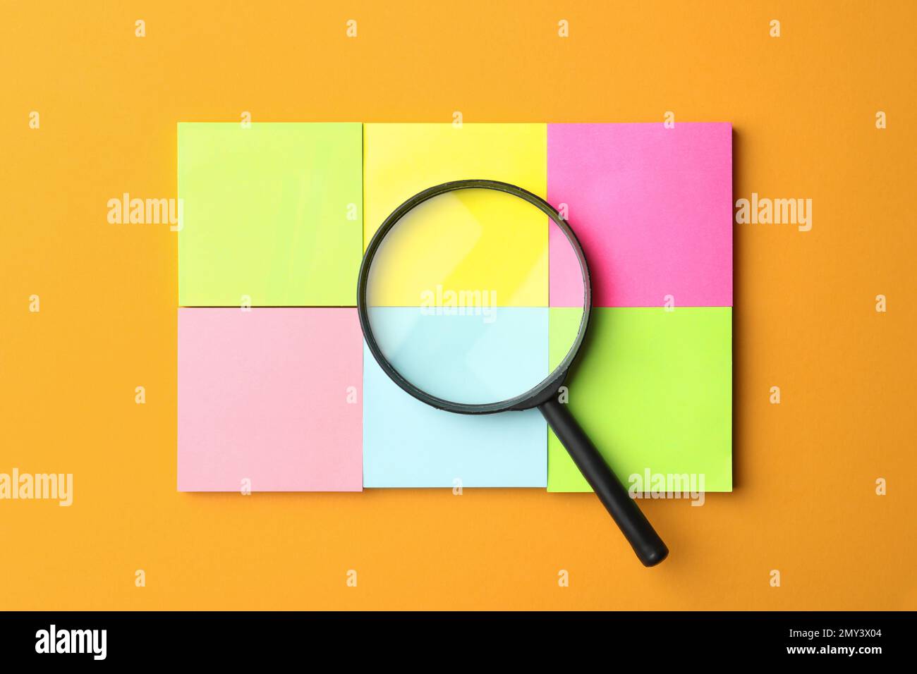 Magnifier glass and different memory stickers on orange background ...