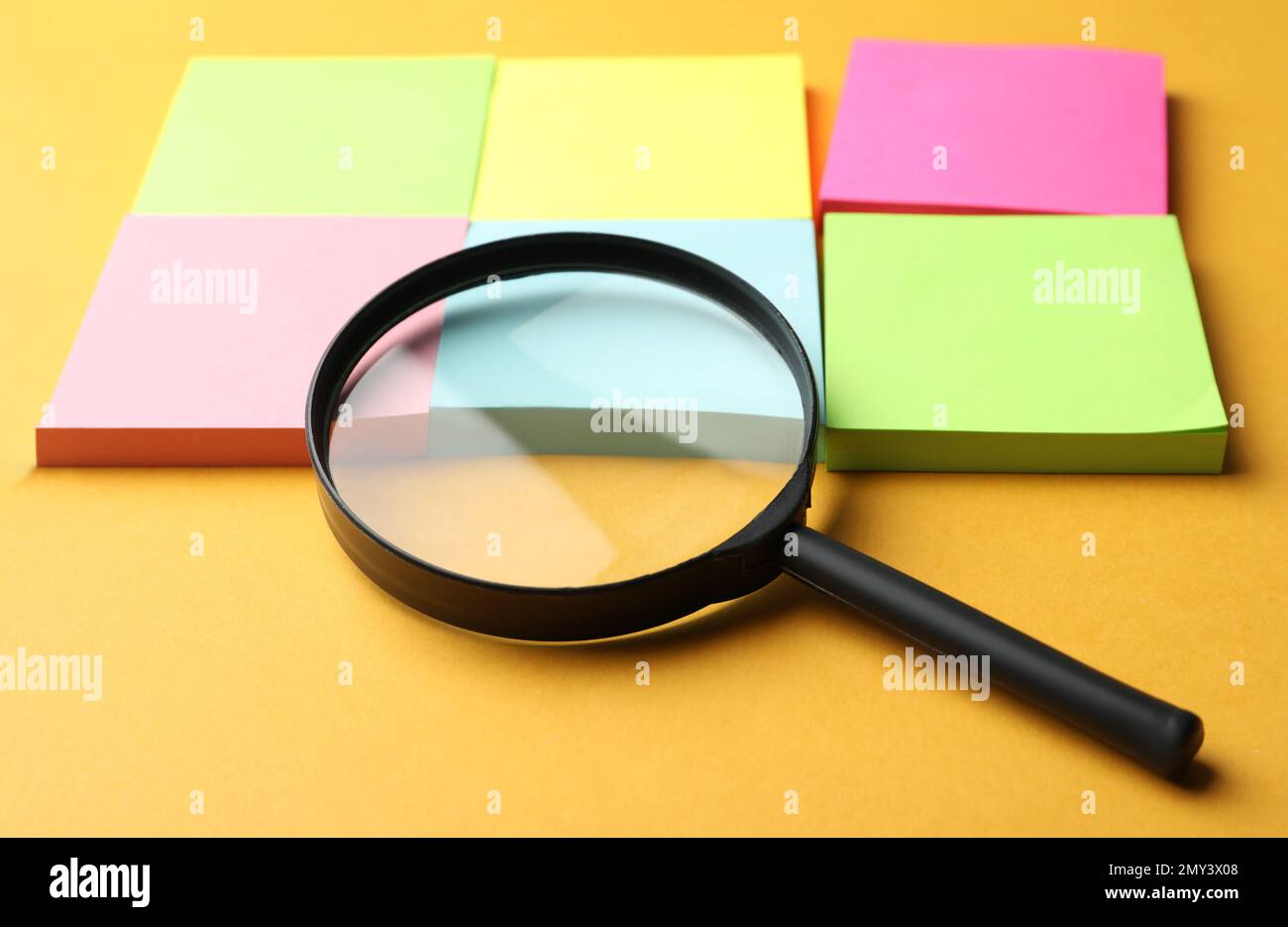 Magnifier glass and different memory stickers on orange background ...