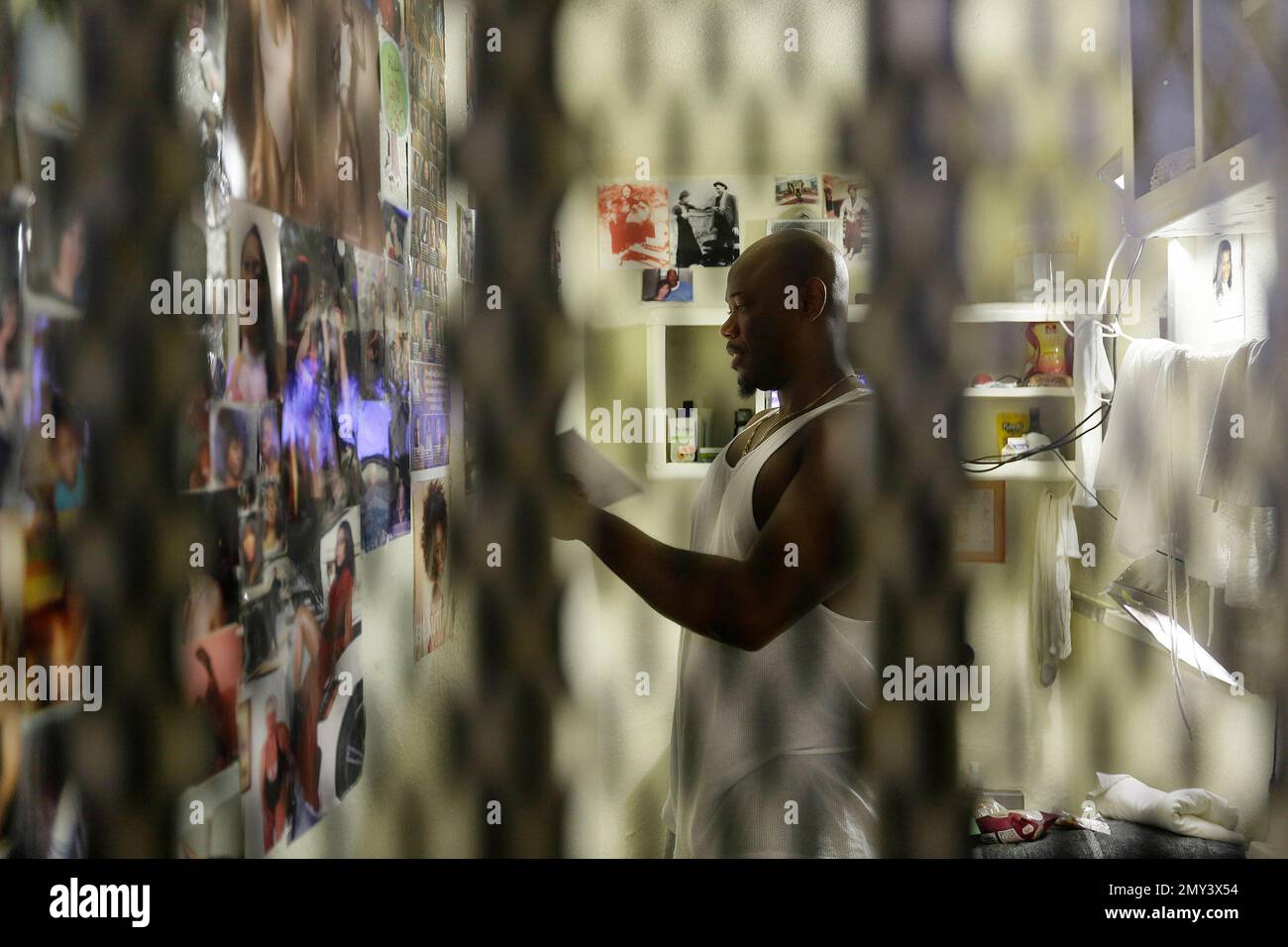 Aswad Pops looks over items photos on the wall of his cell in the east ...