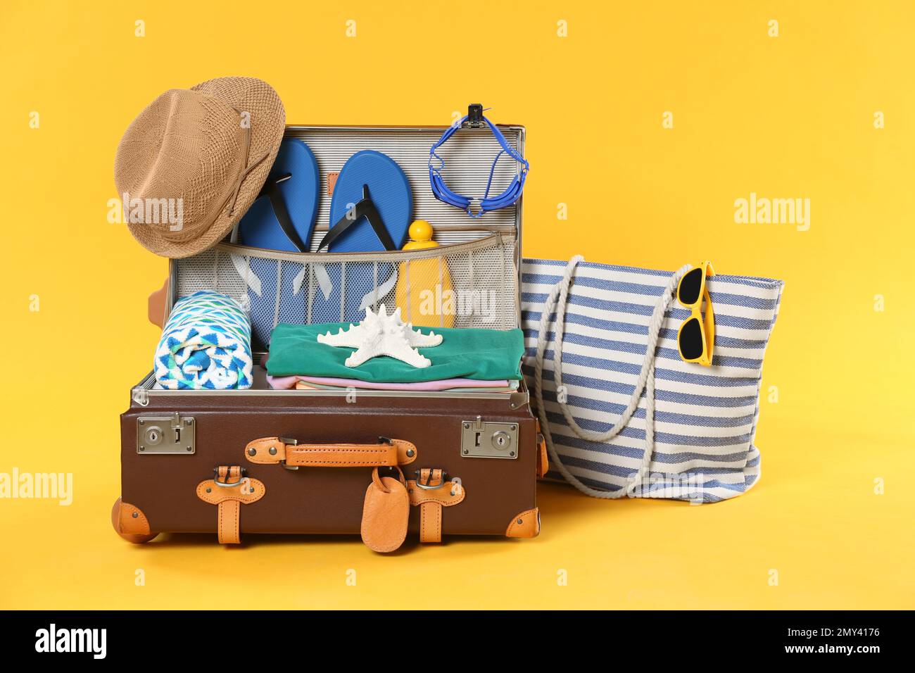 Bag and open vintage suitcase with different beach objects packed for ...