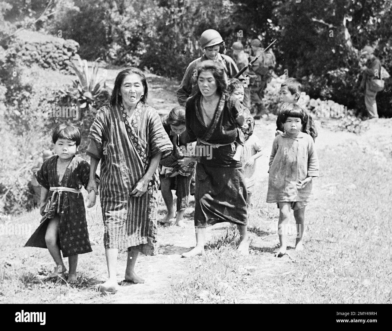 Japanese women and children are moved down a road in Okinawa shortly ...