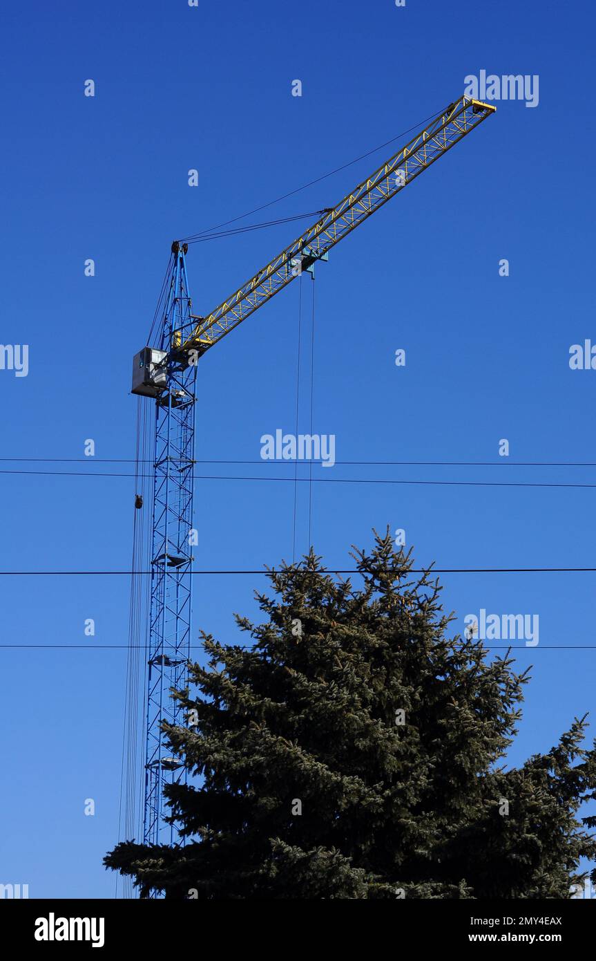 Tall tower crane on construction site, on blue sky background. Spruce ...
