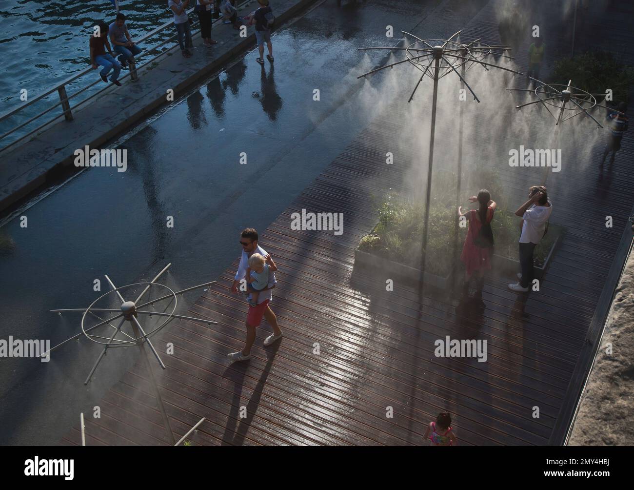 People stand under a shower at Paris Plage along the Seine river in ...