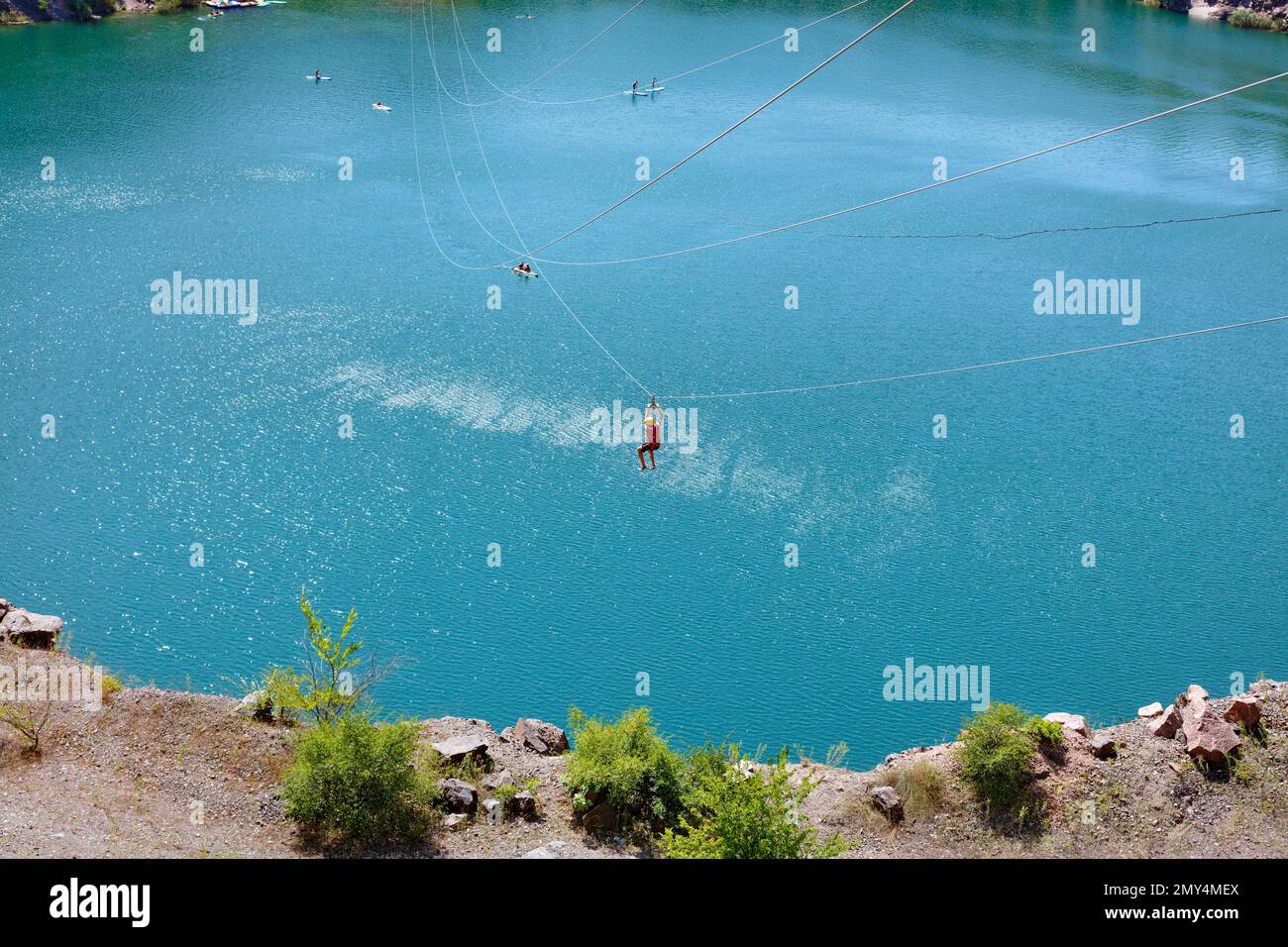 Tourists cross a large lake by cable car through an abandoned granite ...
