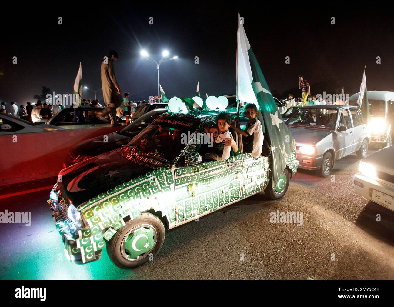 A Pakistan family decorate their car with national flags while they ...