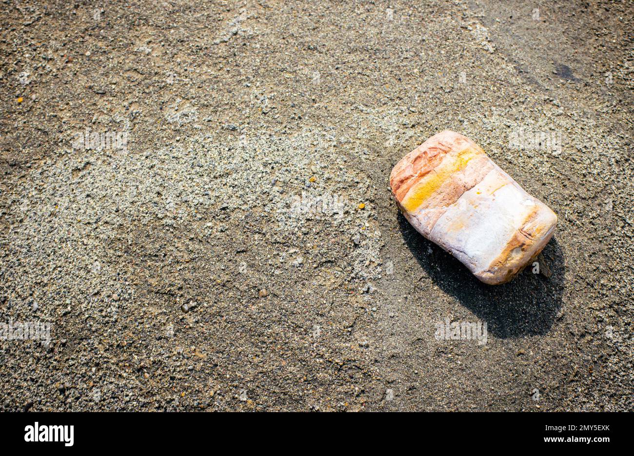 Beautiful isolated rock with texture and colorful layers lay on sand ...