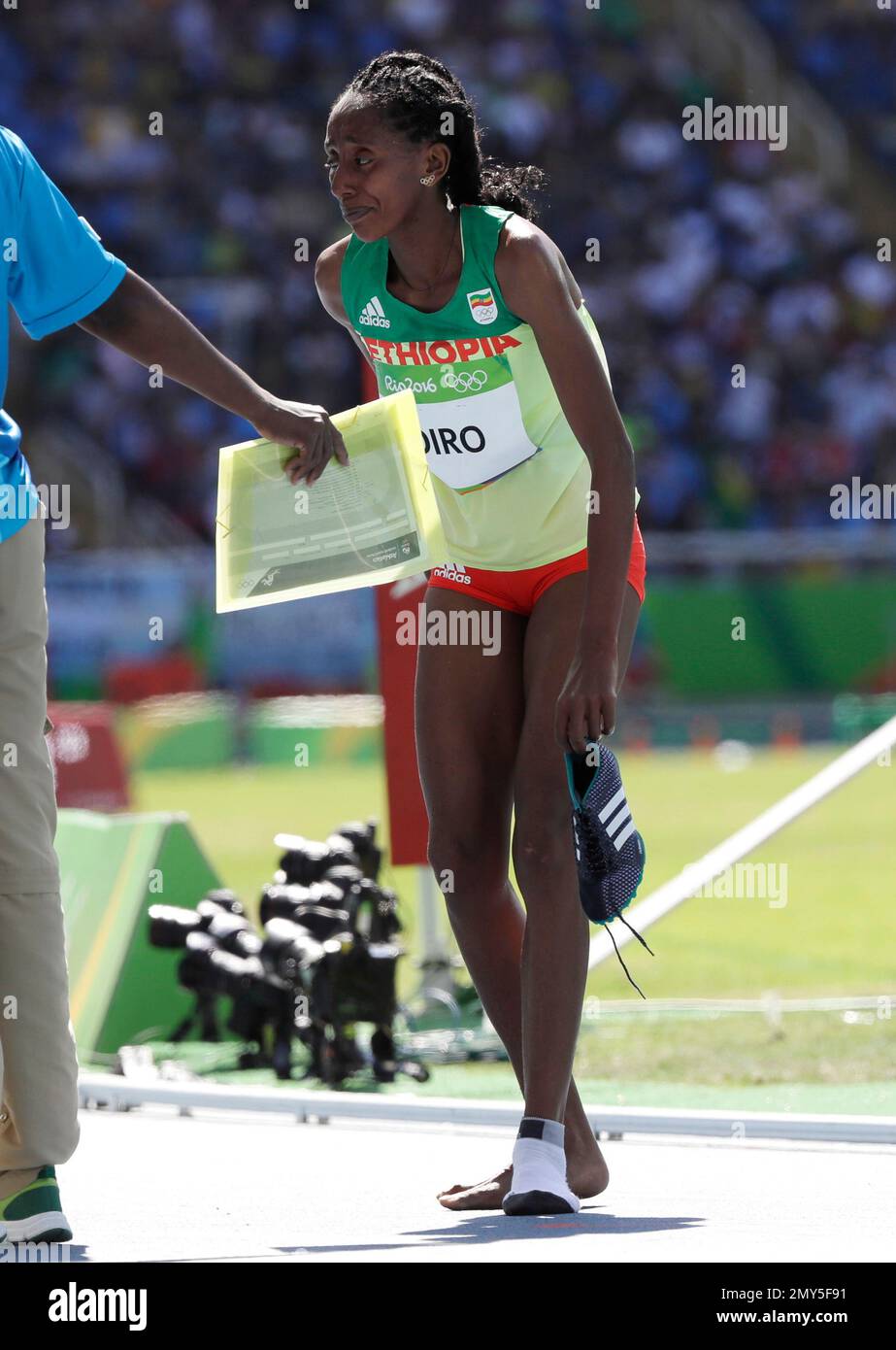 Ethiopia's Etenesh Diro leaves the track carrying her shoe after a ...