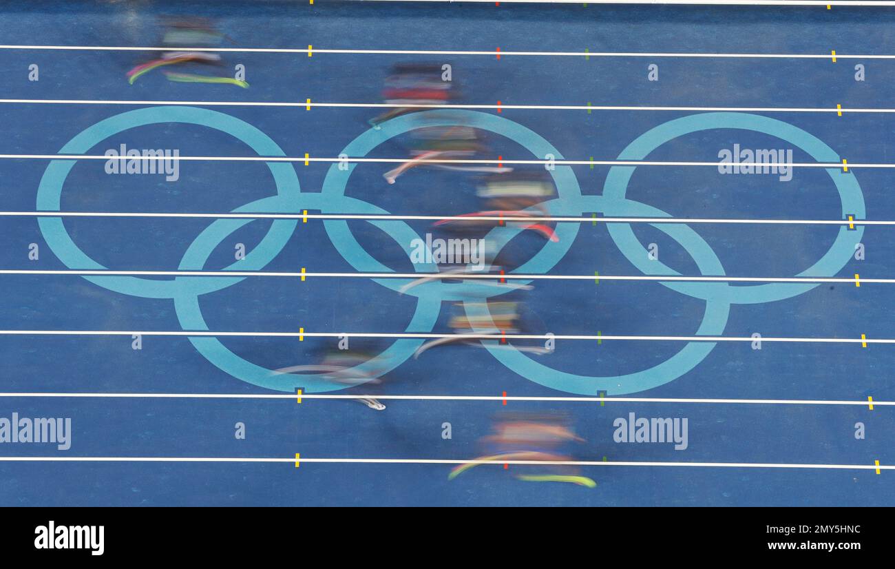 In this image taken with a slow shutter speed, runners race in a 100 ...