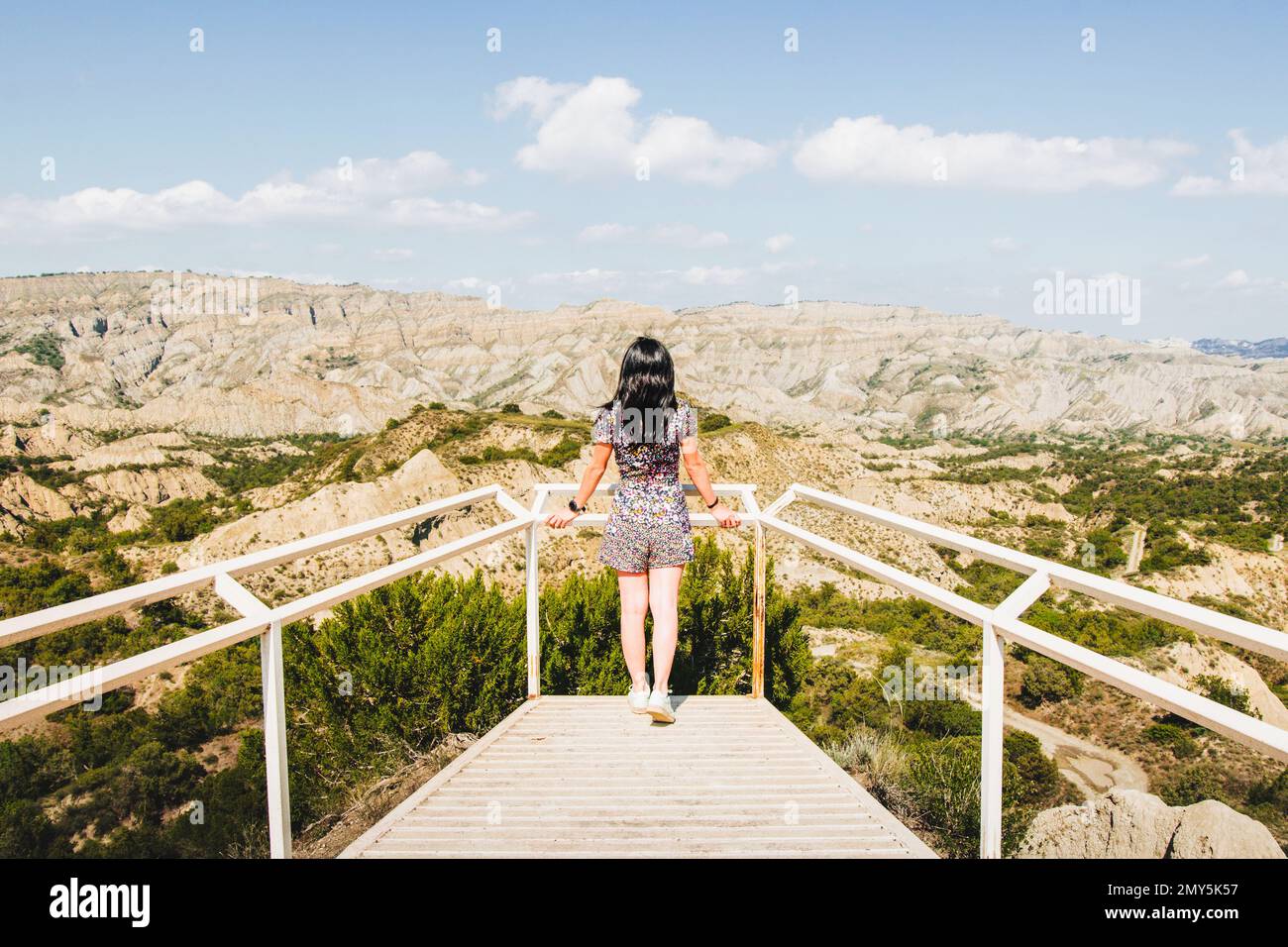 Brunette woman stands on the platform viewpoint and looks left over ...