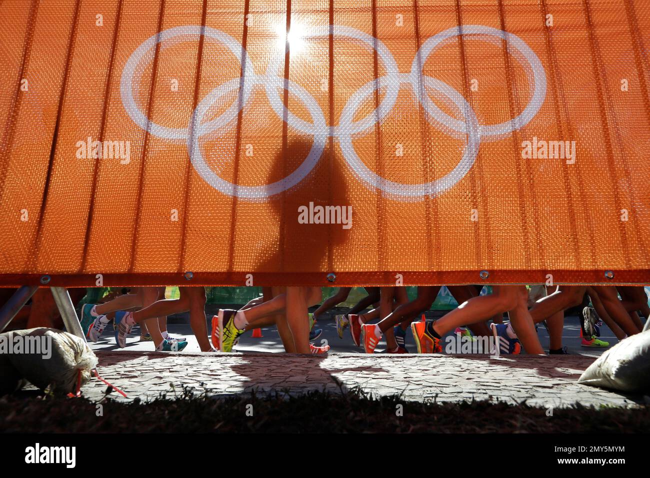 An athlete casts a shadow on a fence while competing in the men's 20km ...