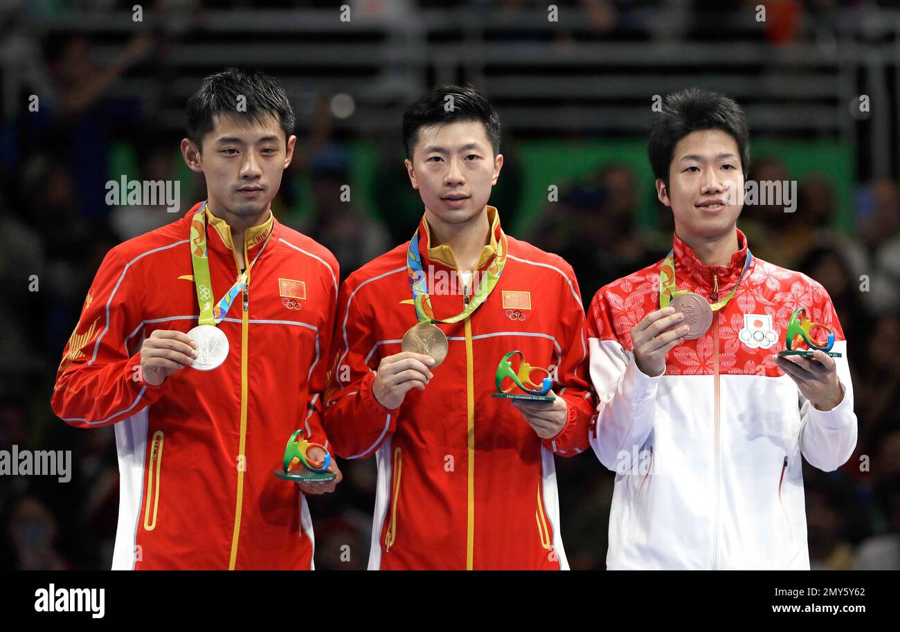 Ma Long, of China, center, holds his gold medal as he stands with ...