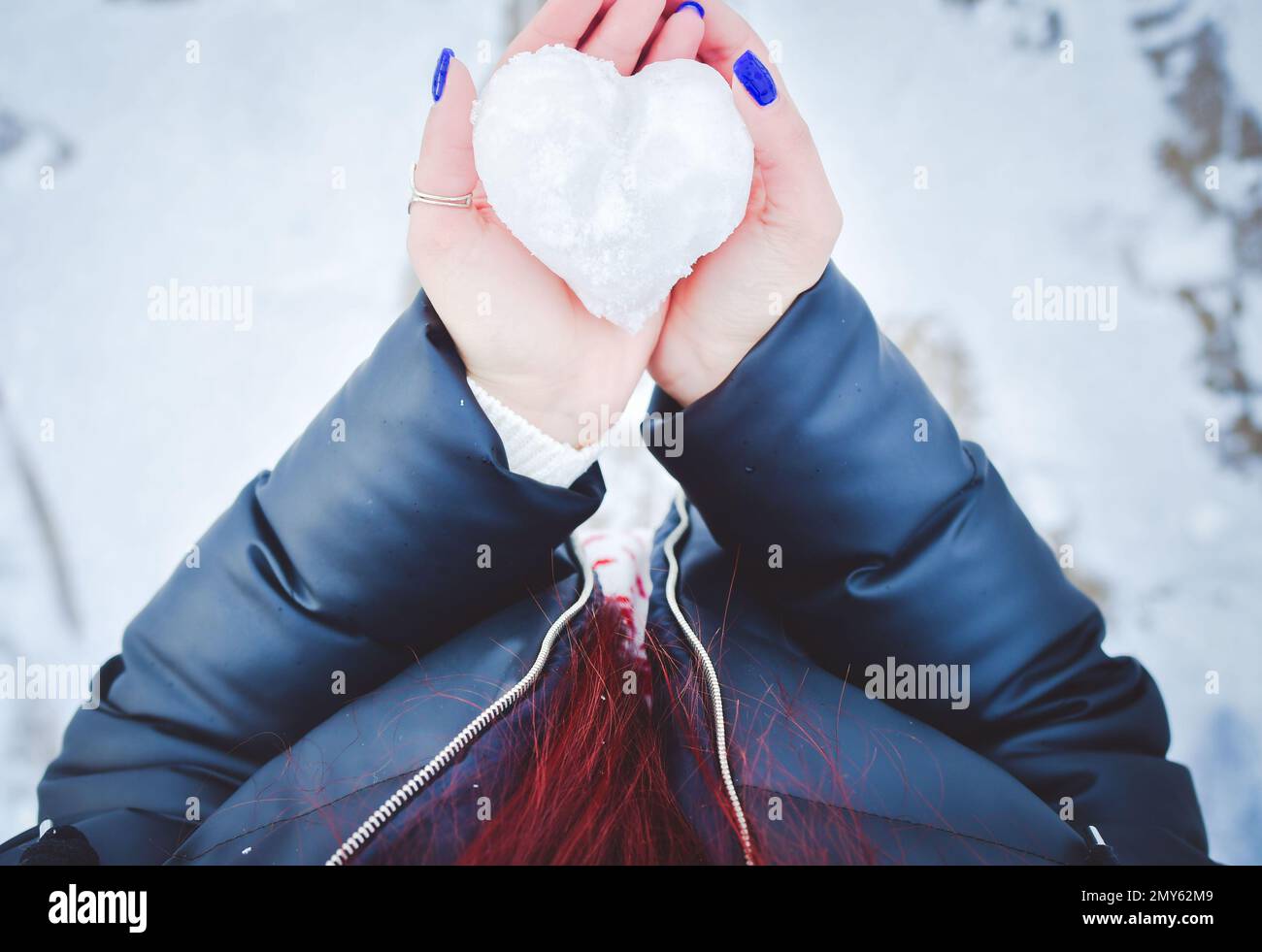 The heart made of snow in female hands. Kindness and care in snowy cold ...