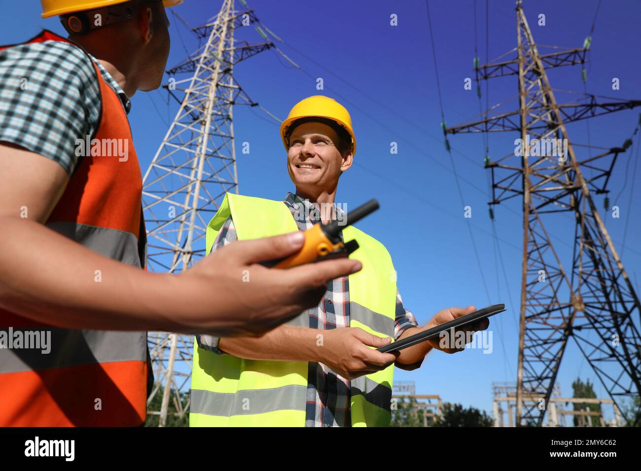 Professional electricians in uniforms near high voltage towers Stock ...