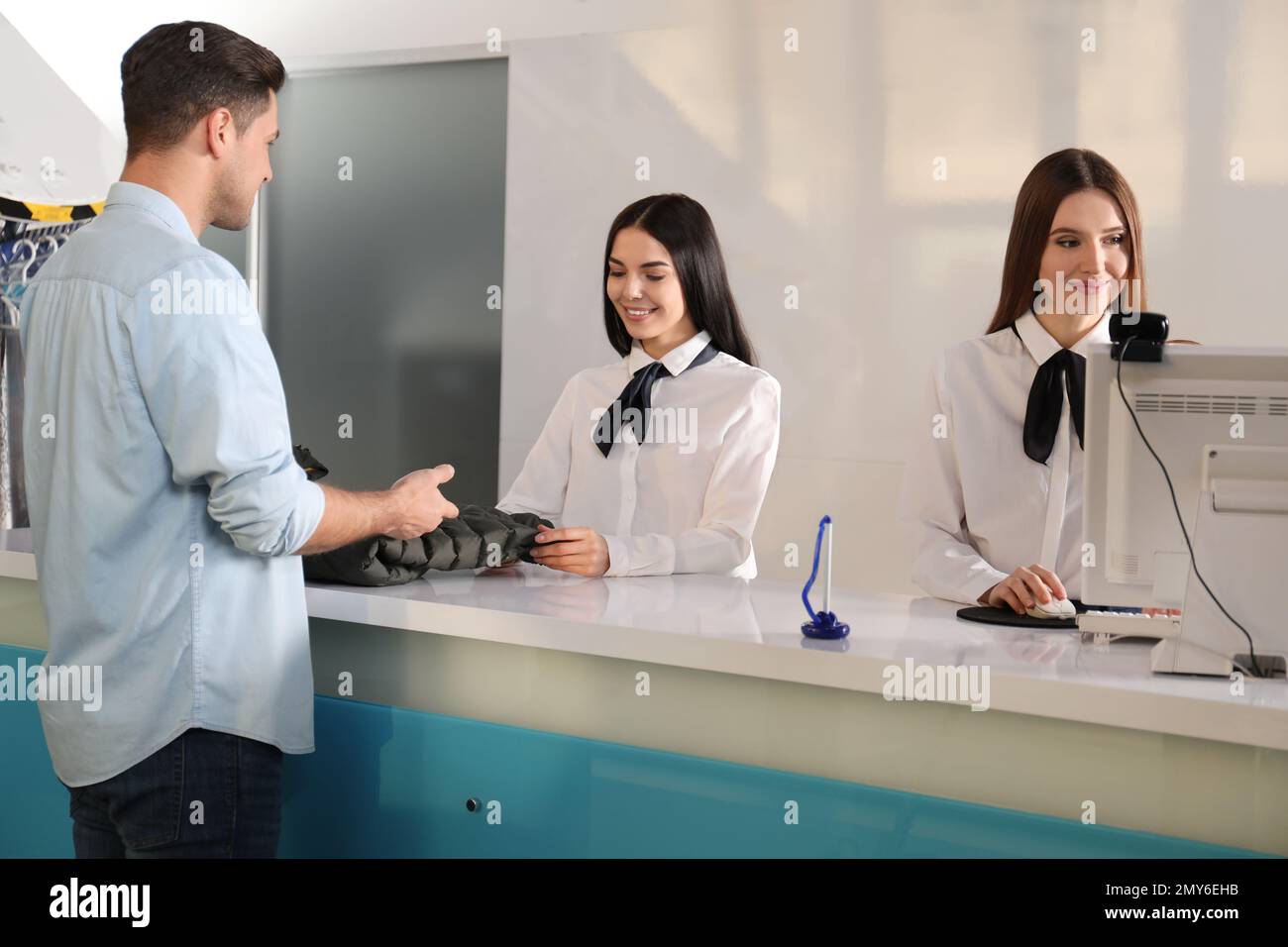 Female employees working with client at dry-cleaner's Stock Photo - Alamy
