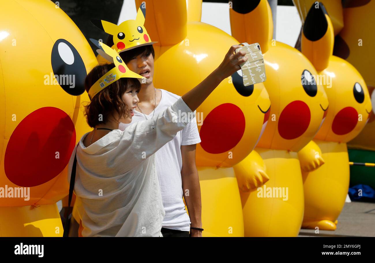 A couple takes a selfee in front of giant toys of Pokemon character Pikachu at Minatomirai ...