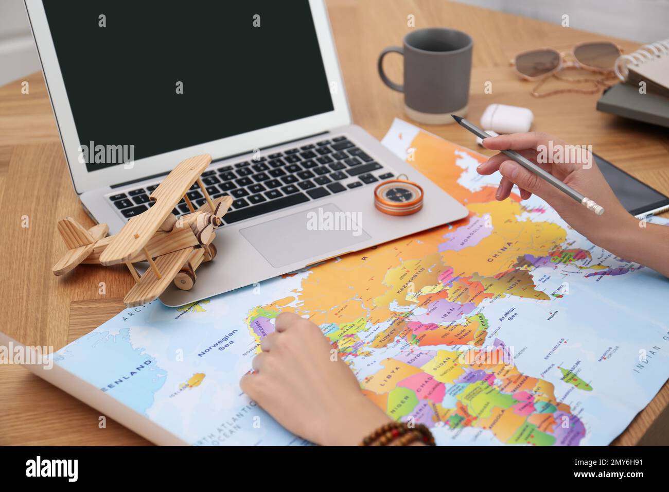 Woman with world map and laptop planning trip at wooden table, closeup ...