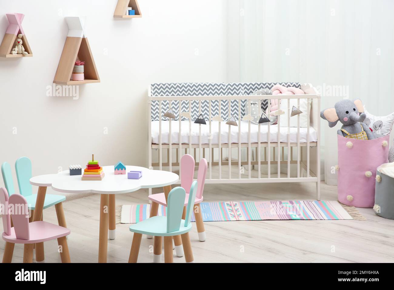 Cute baby room interior with cot and little table Stock Photo - Alamy