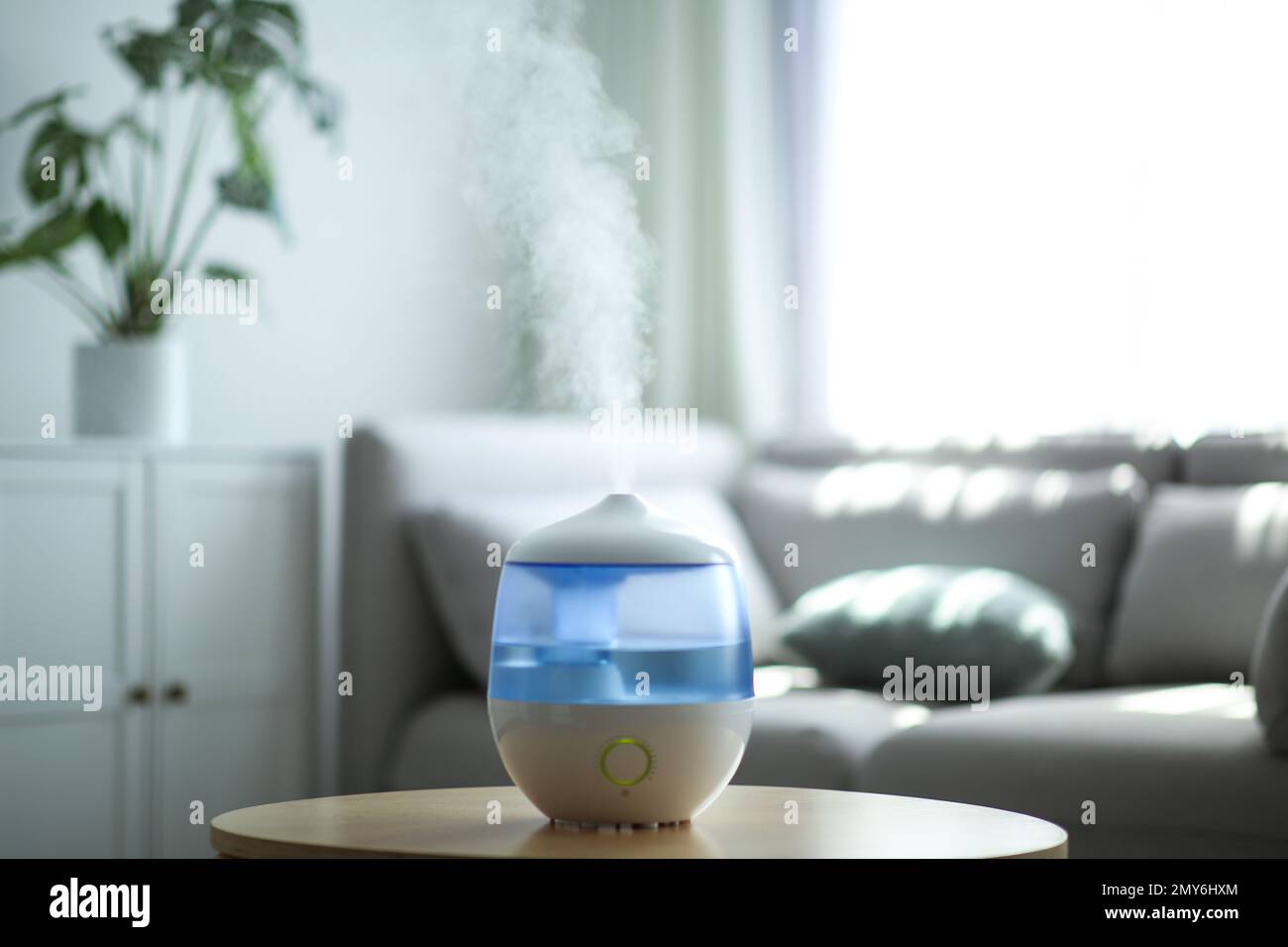 Modern air humidifier on table in living room Stock Photo - Alamy