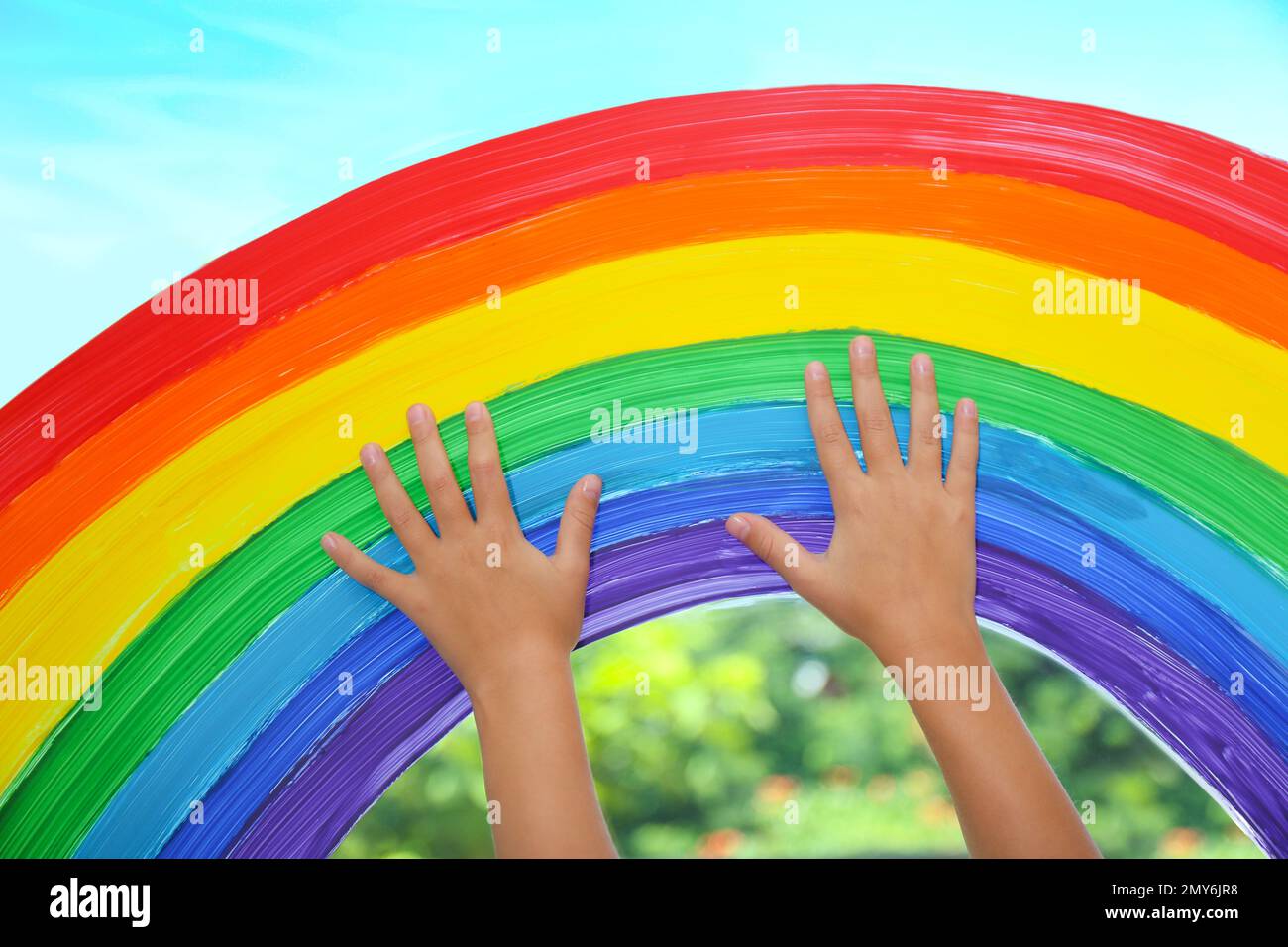 Child touching picture of rainbow on window, closeup. Stay at home ...