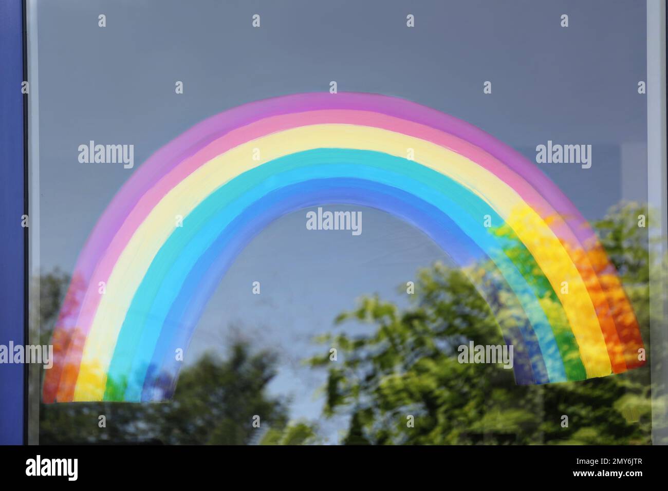 Painting of rainbow on window, view from outdoors. Stay at home concept ...
