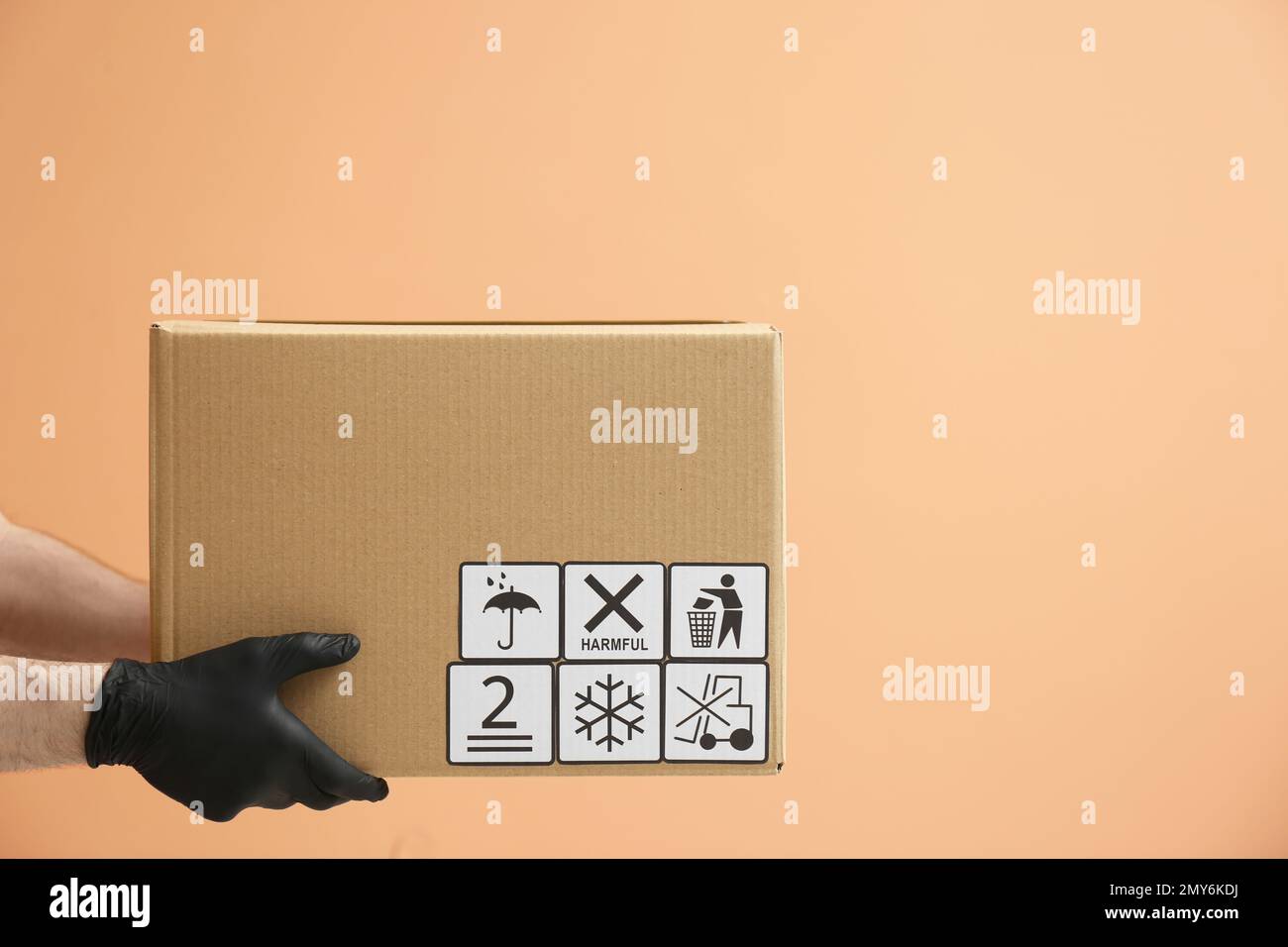 Courier holding cardboard box with different packaging symbols on ...