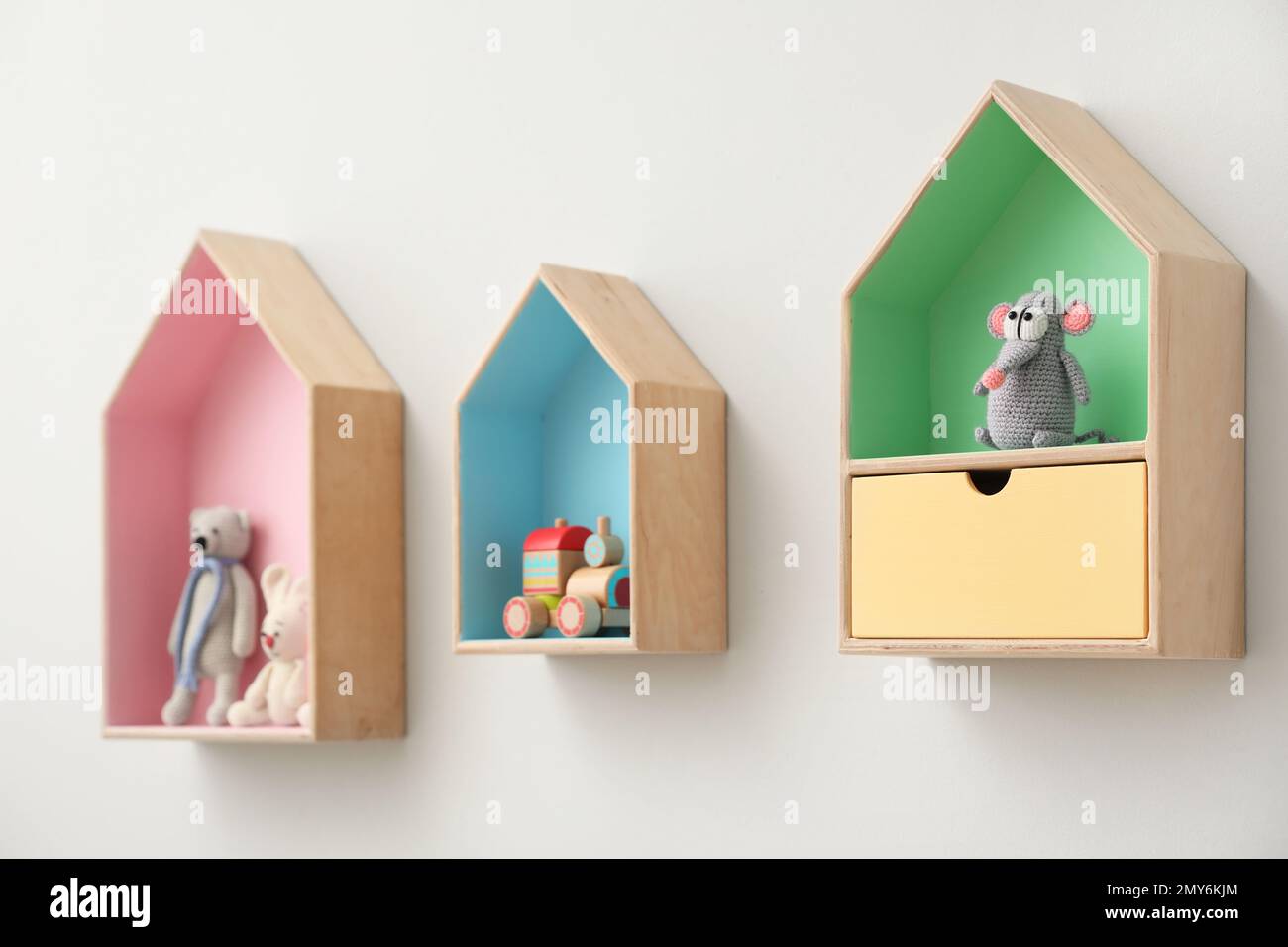 Stylish house shaped shelves with toys on white wall. Baby room ...