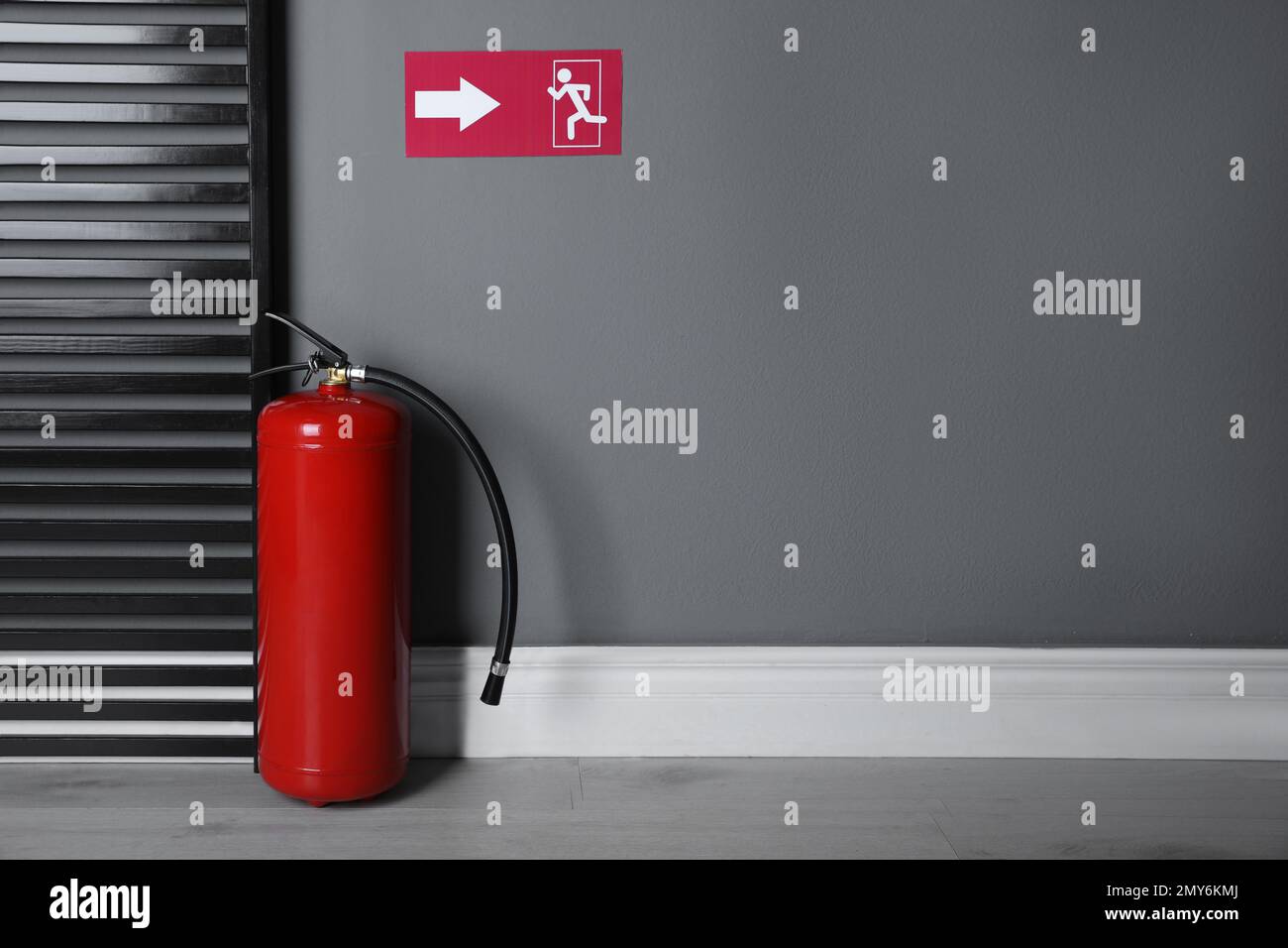 Fire extinguisher and emergency exit sign indoors. Space for text Stock ...