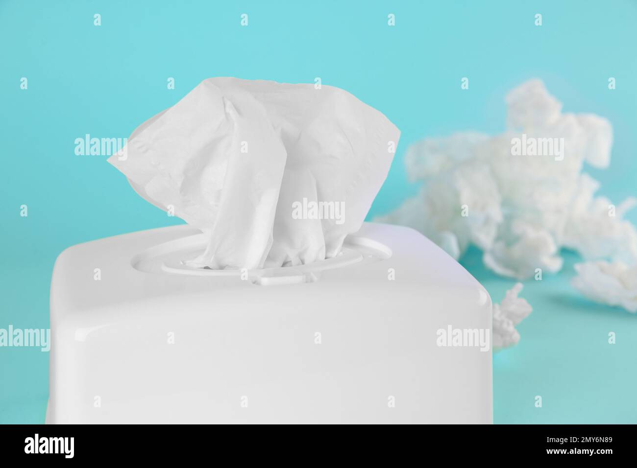 Used paper tissues and white holder on light blue background, closeup ...