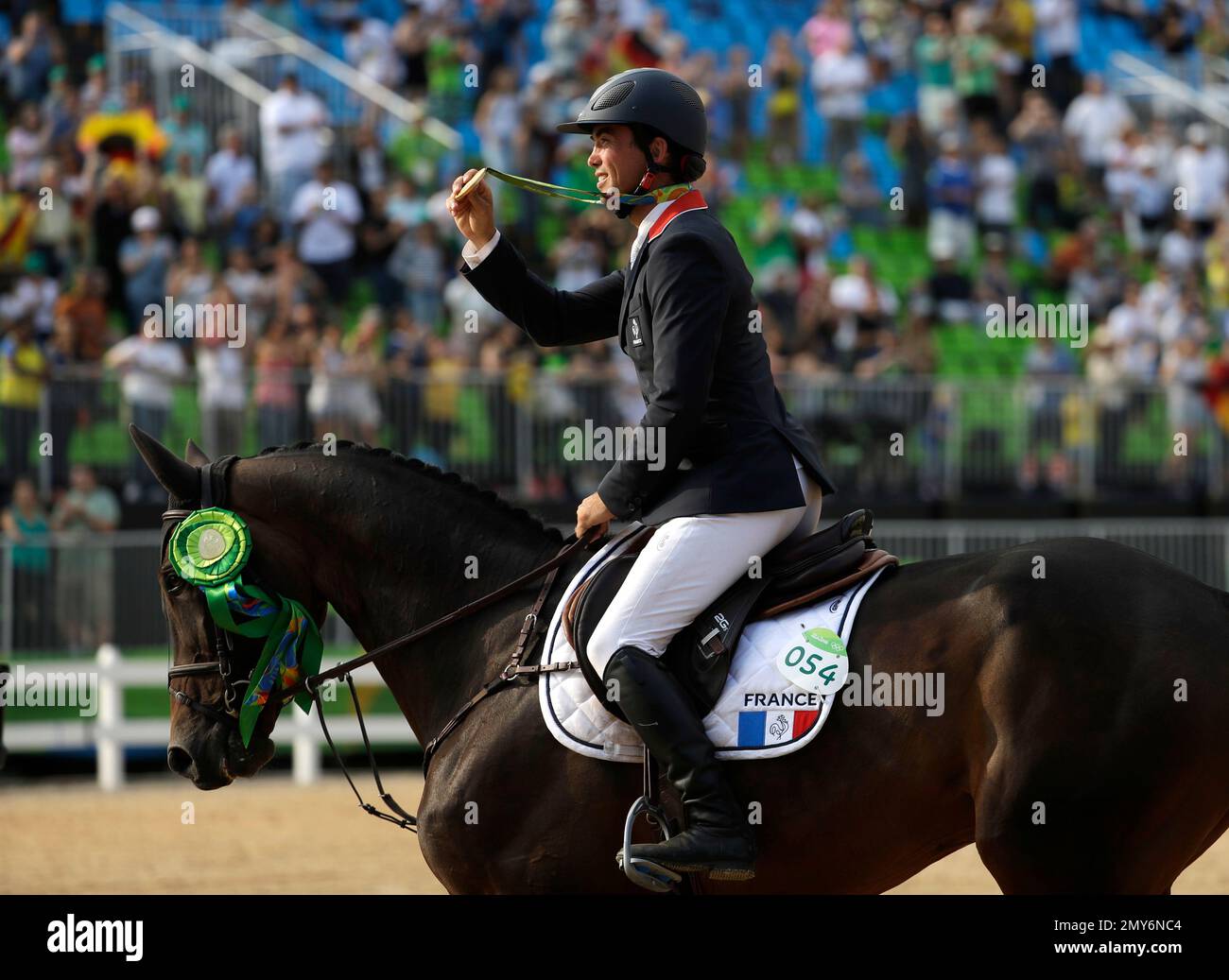 Mathieu Lemoine, of France, riding Bart L, shows off his gold medal at the equestrian team ...