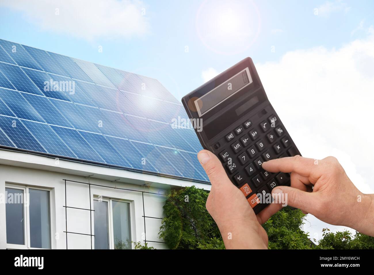 Man using calculator against house with installed solar panels ...