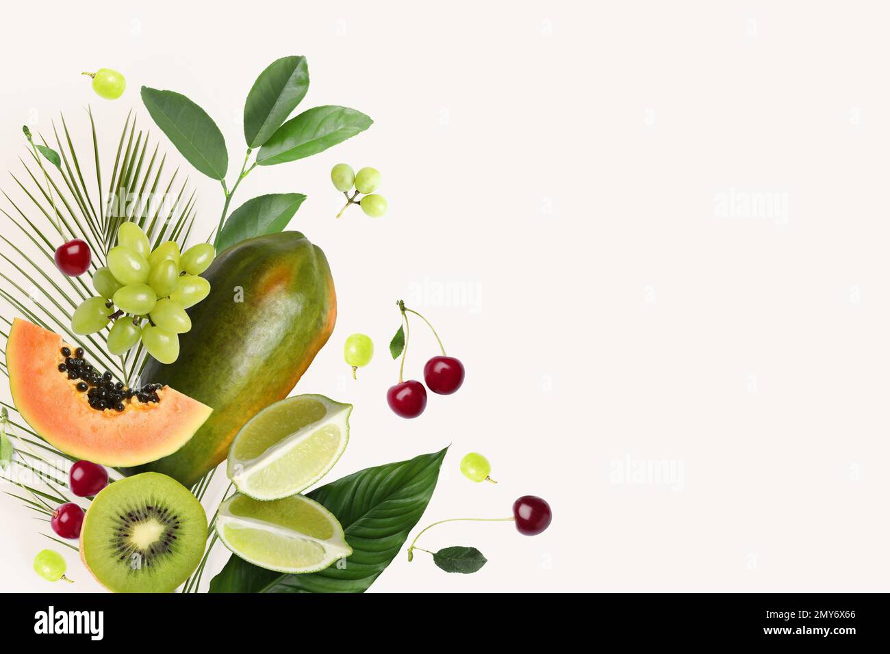 Tropical layout with fresh exotic fruits and green leaves on light ...