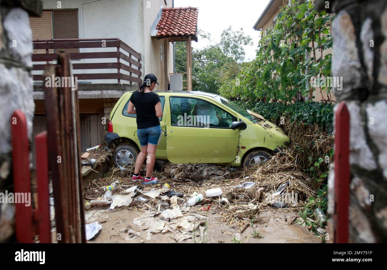 A woman stands by a damaged car in the house yard after flooding, in ...